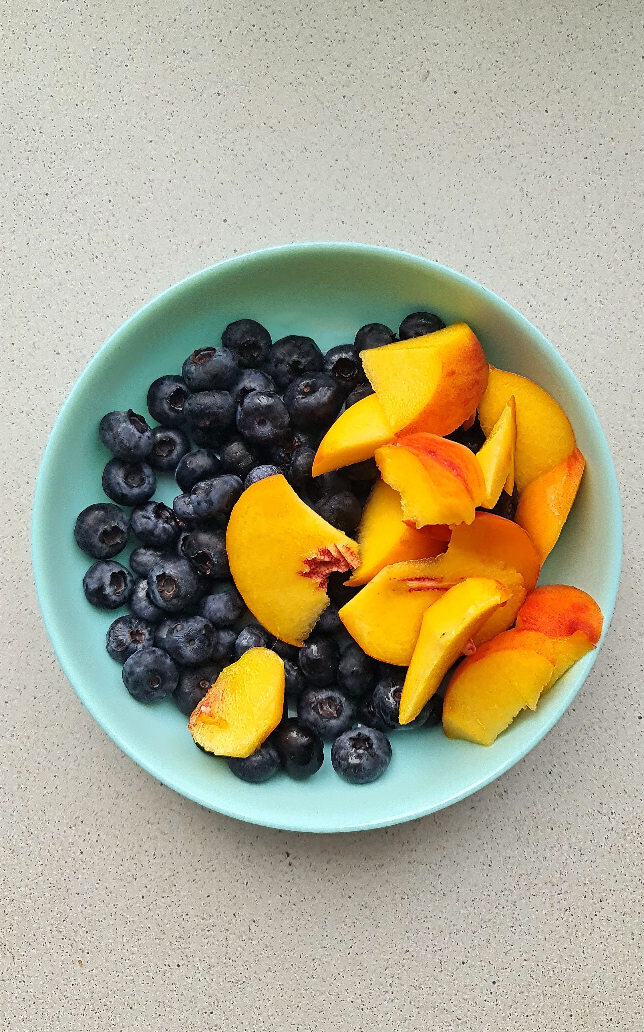 A bowl of blueberries and peaches with a spoon · Free Stock Photo