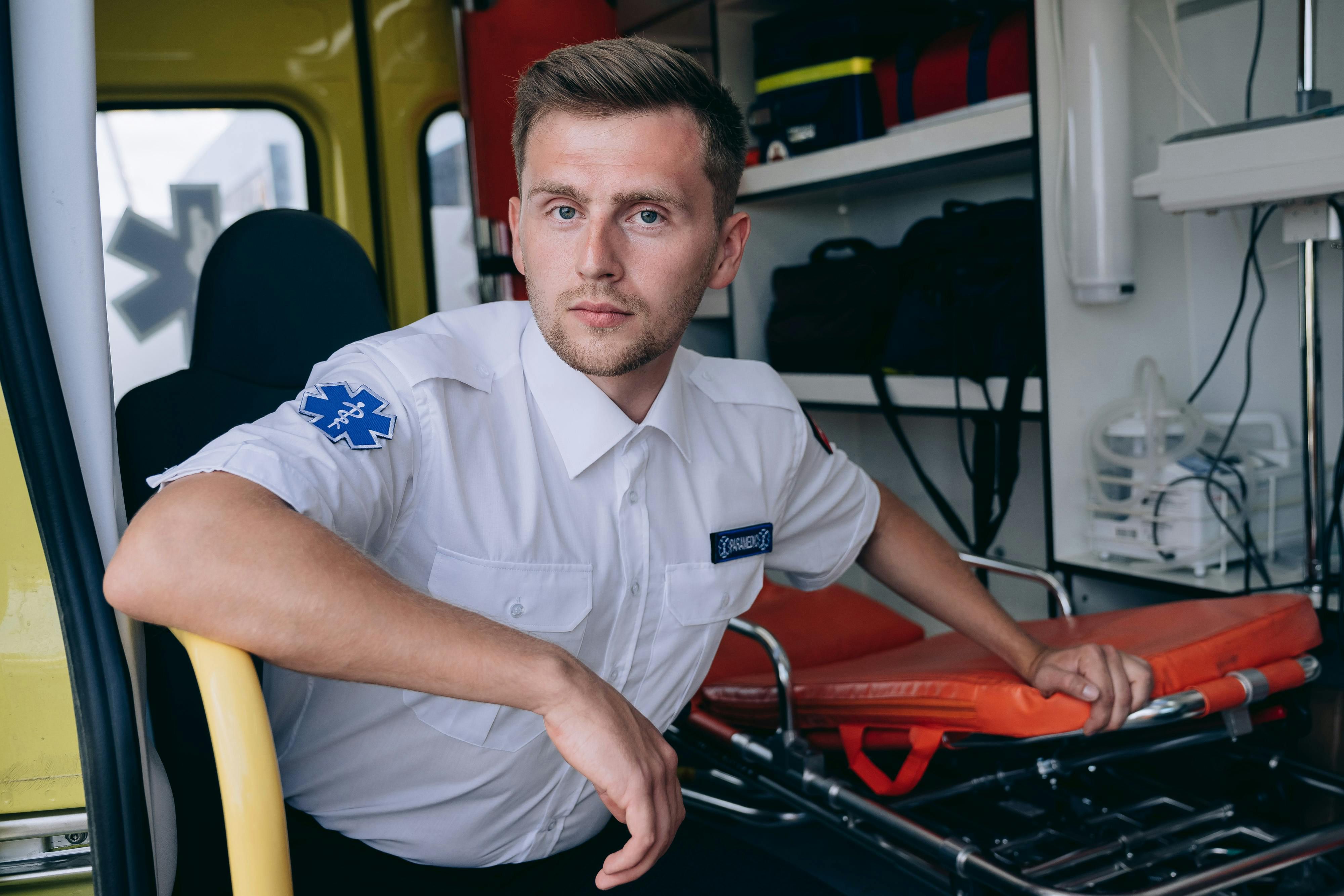 Paramedic Sitting Next to a Stretcher in an Ambulance · Free Stock Photo