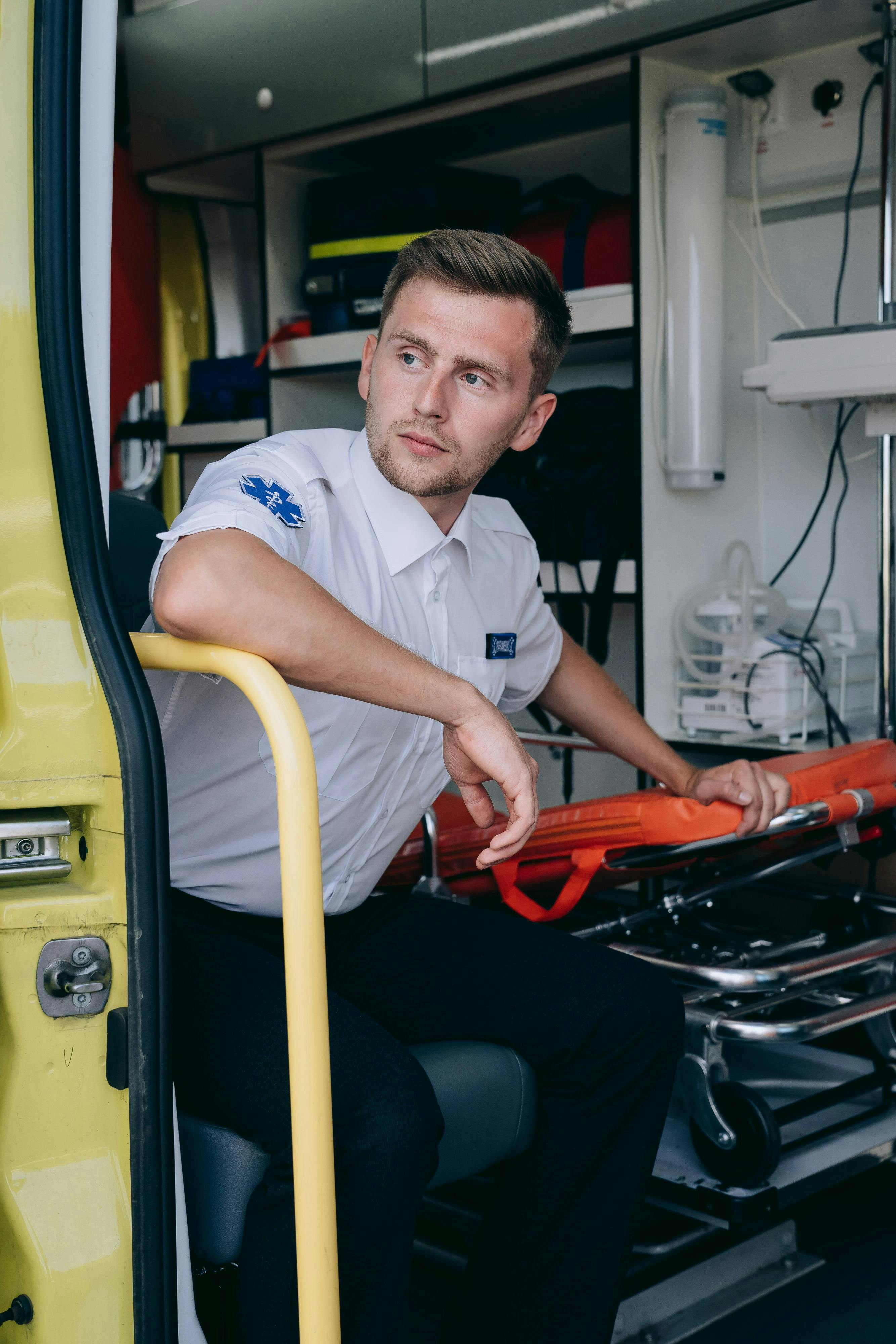 Paramedic Sitting by the Gurney in an Ambulance · Free Stock Photo