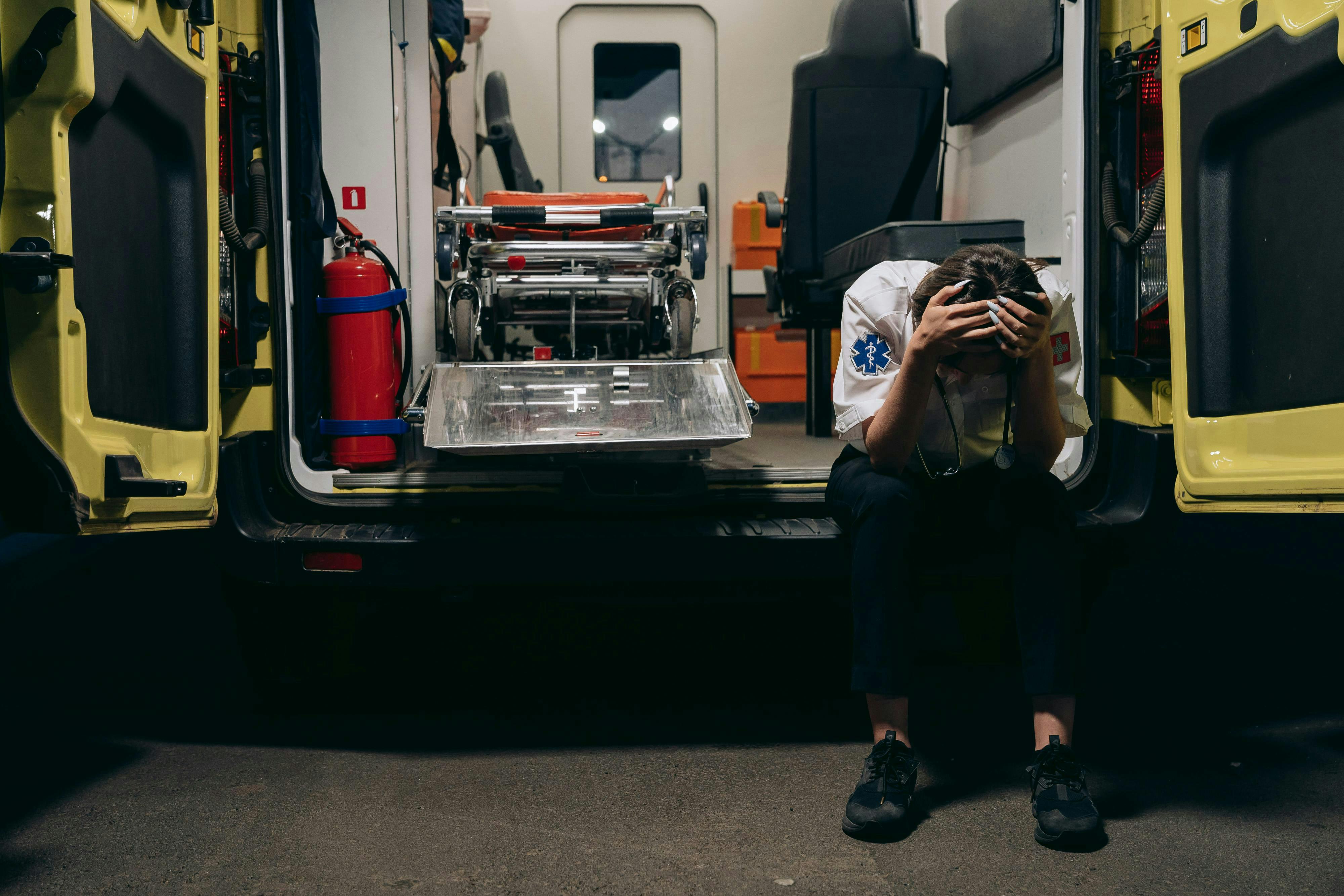 Paramedic Sitting on the Bumper of an Ambulance with Head in Hands ...