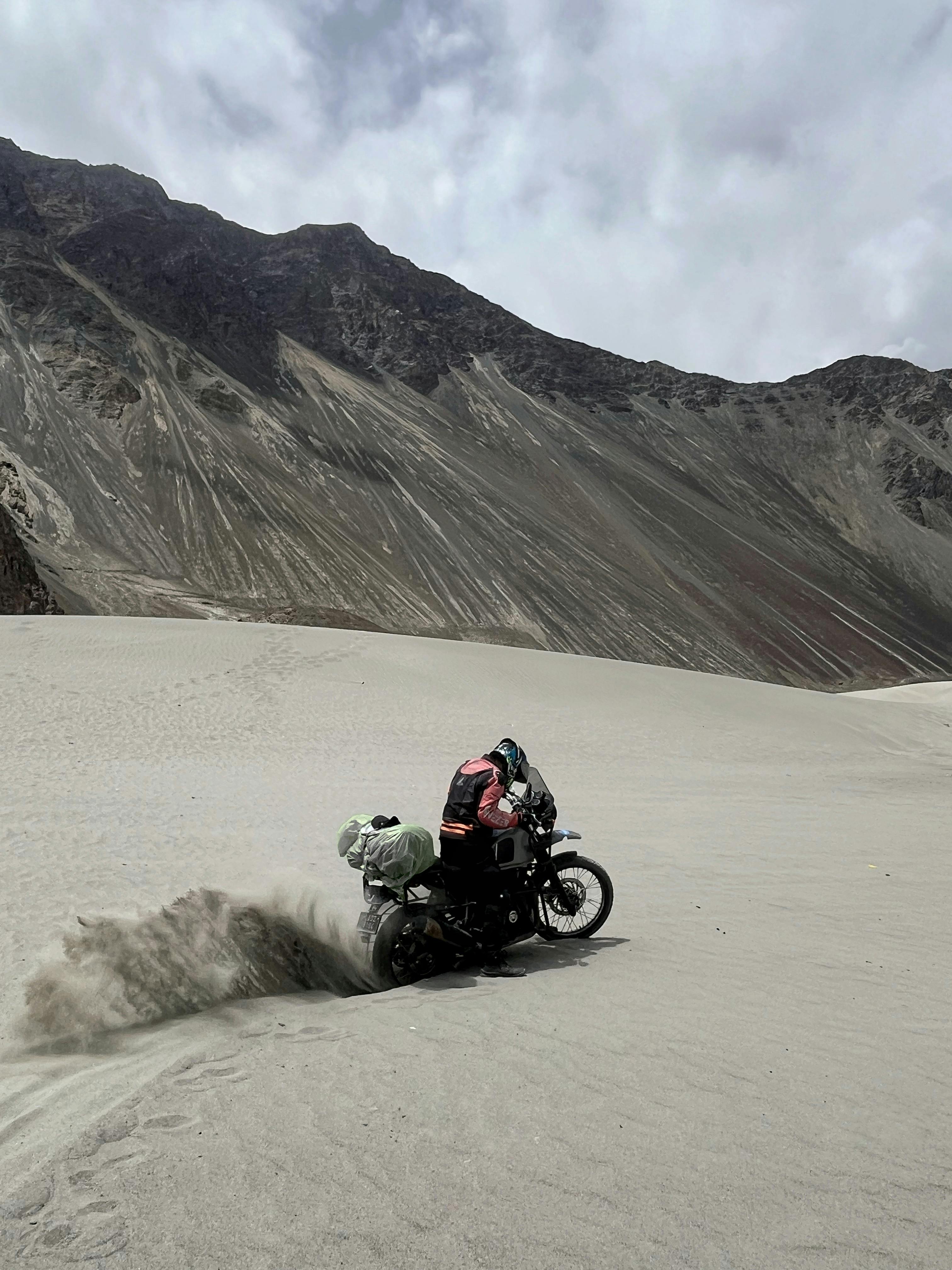 A person riding a motorcycle on a sandy desert · Free Stock Photo