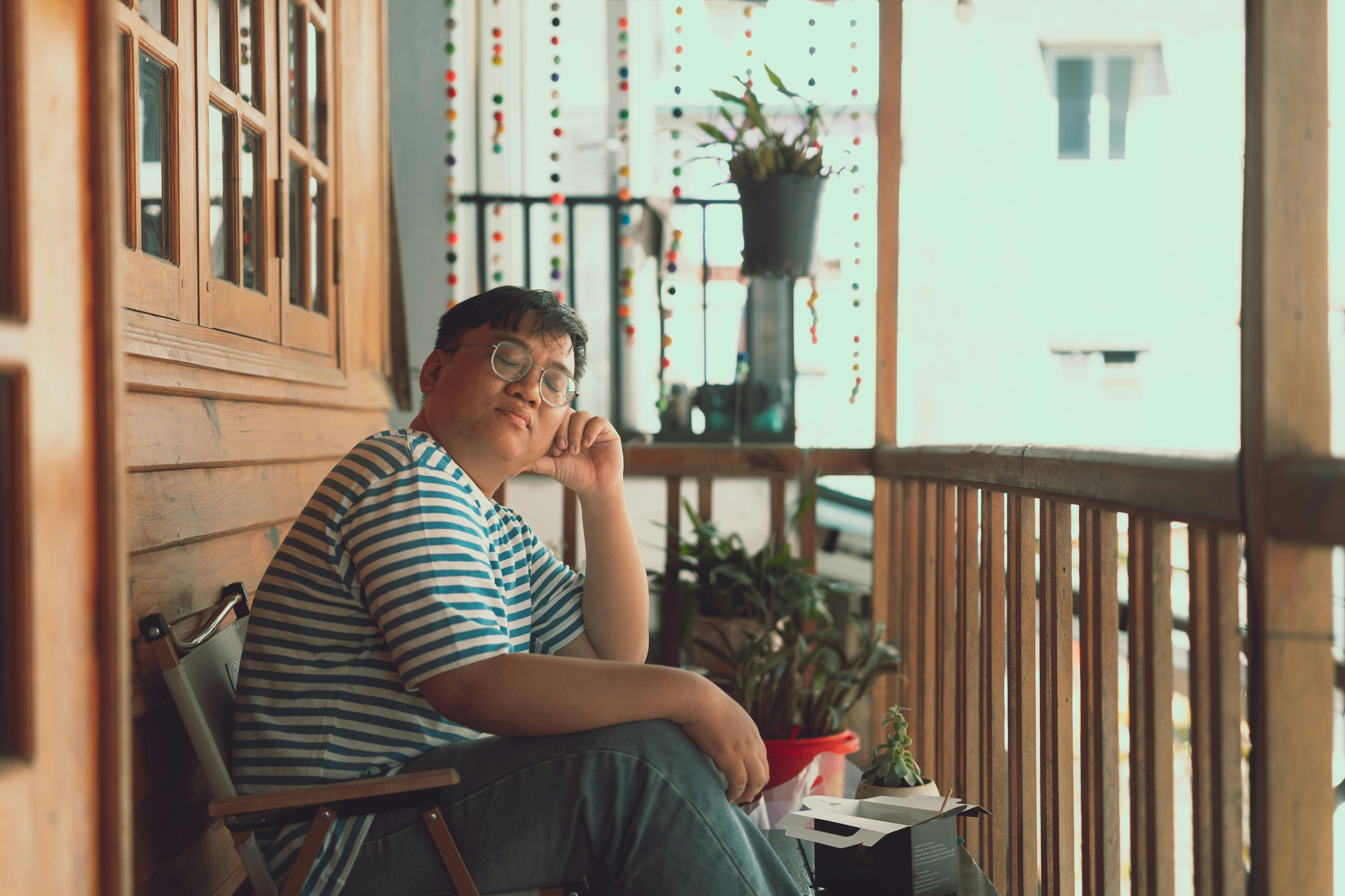 A man sitting on a porch talking on a cell phone · Free Stock Photo