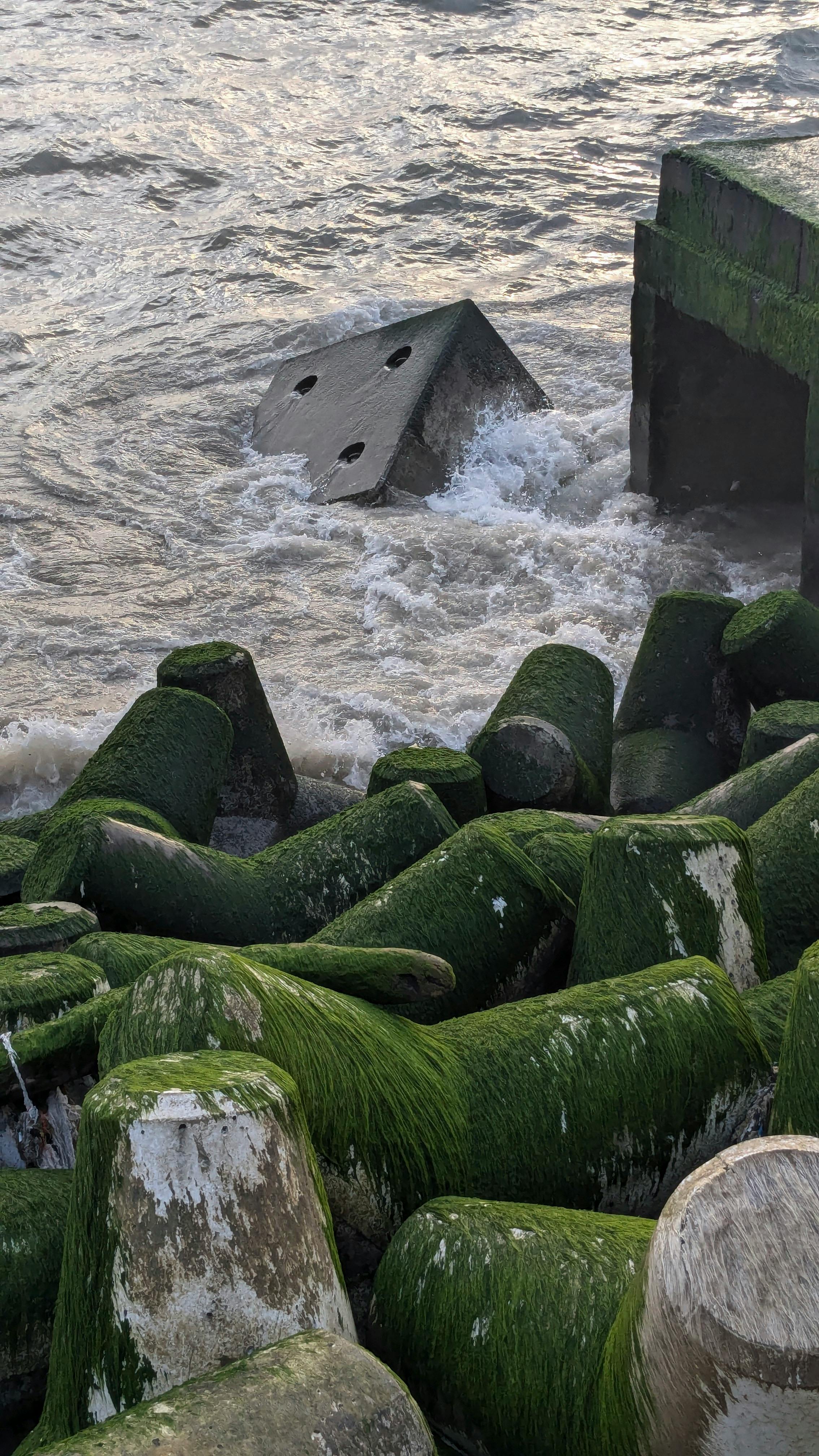 A large green rock is sitting on the beach · Free Stock Photo