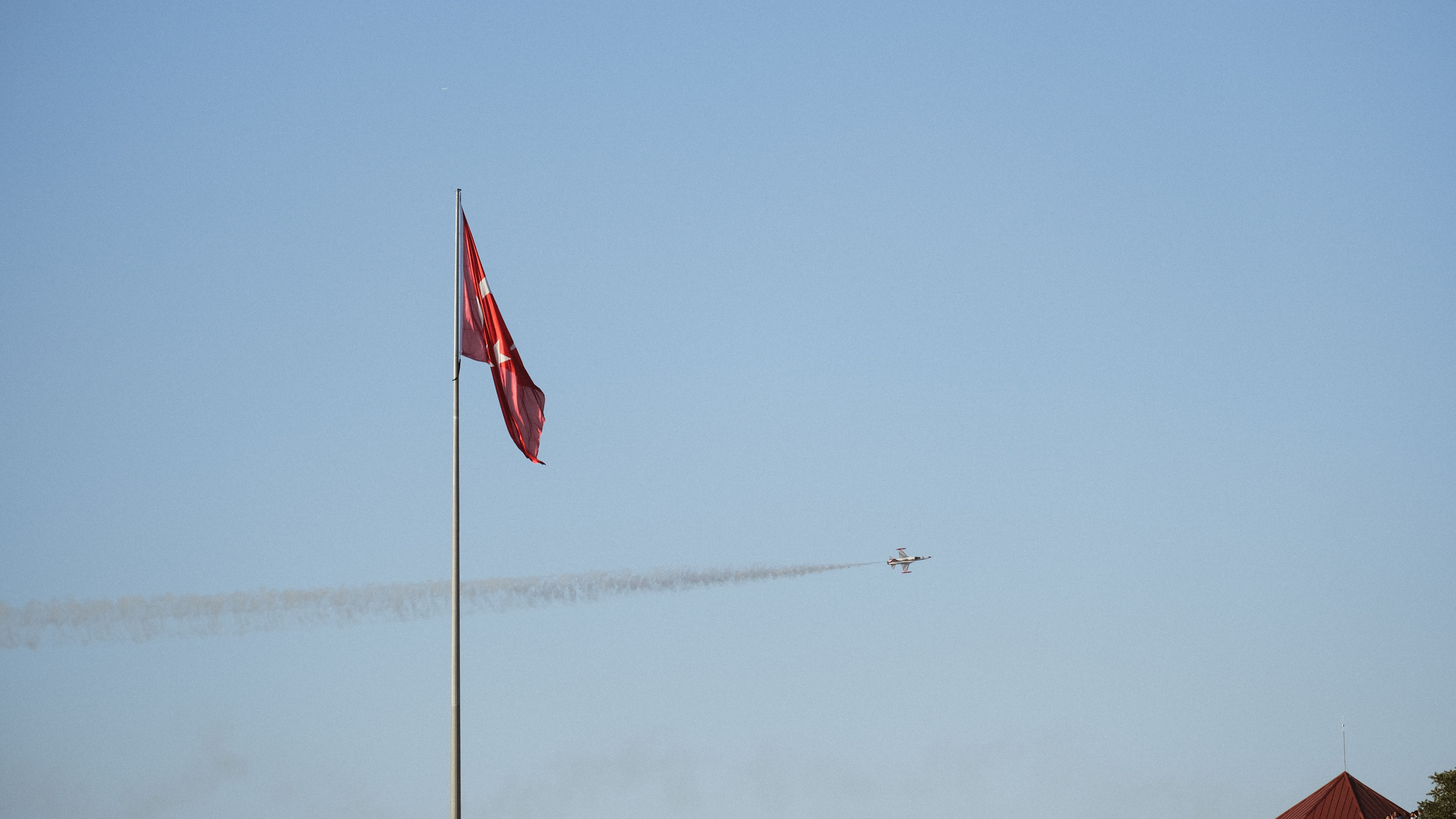 A plane flying over a flag with smoke coming out of it · Free Stock Photo