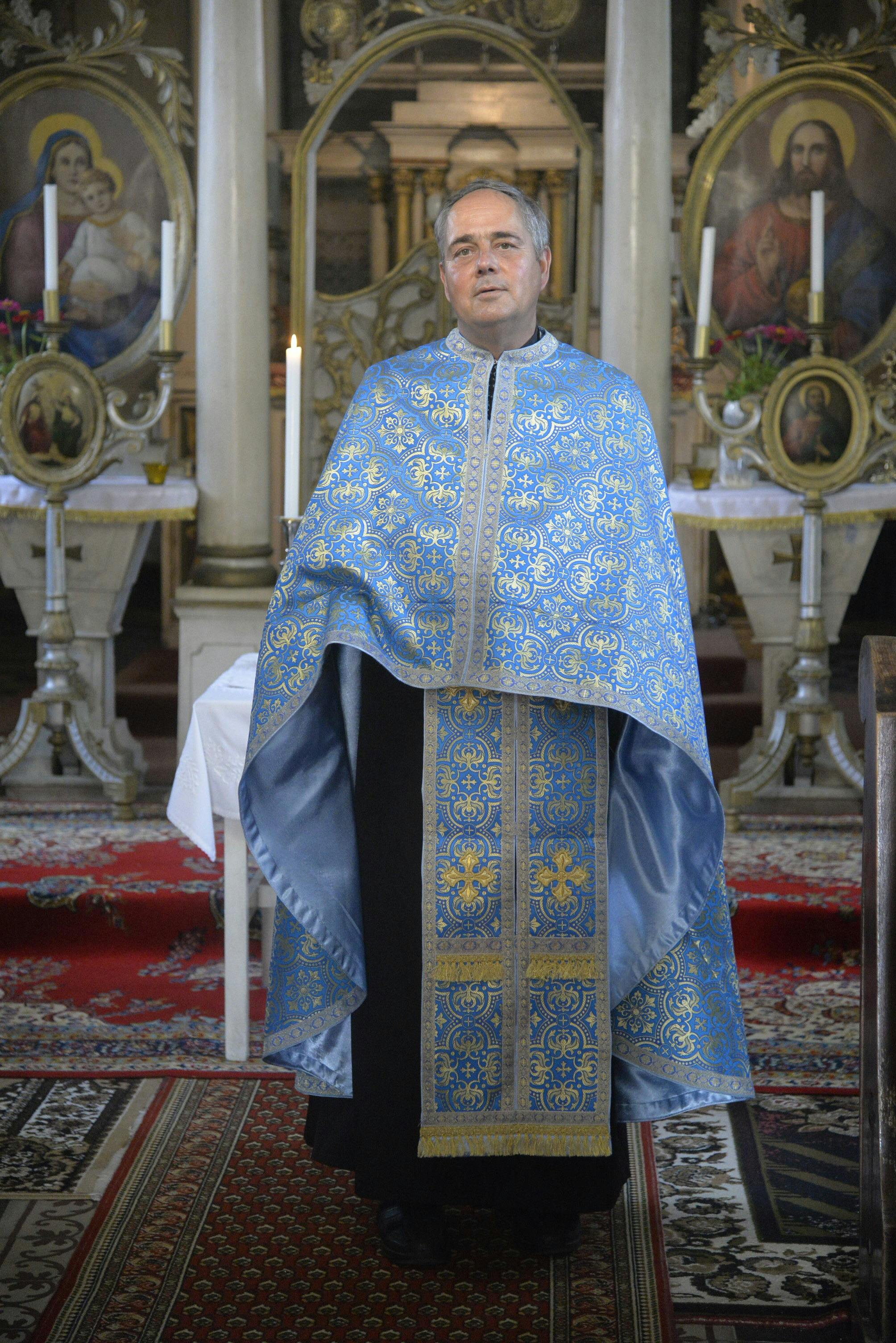 A man in a blue and gold robe standing in front of a church · Free ...