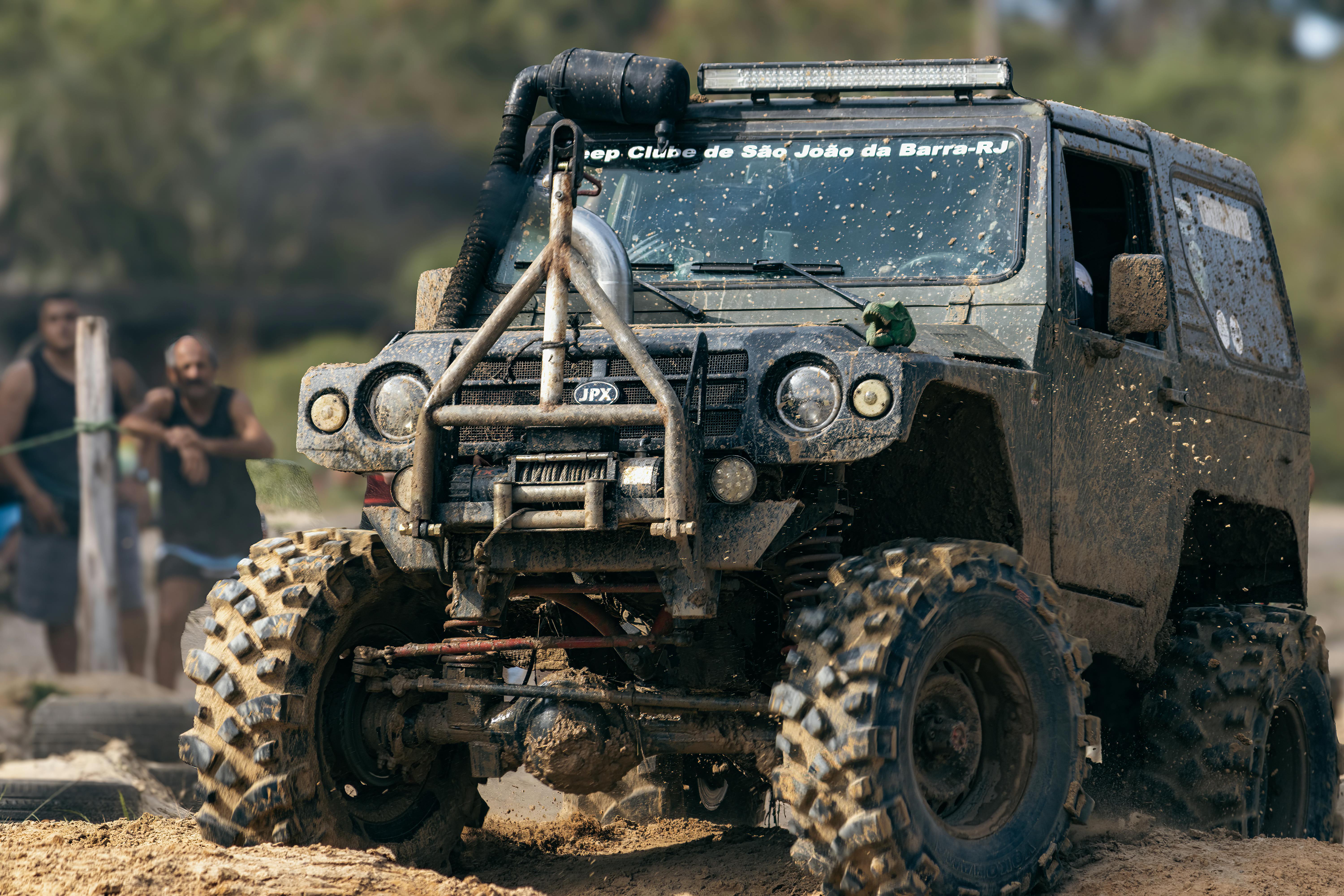 A jeep with mud tires driving through the mud · Free Stock Photo