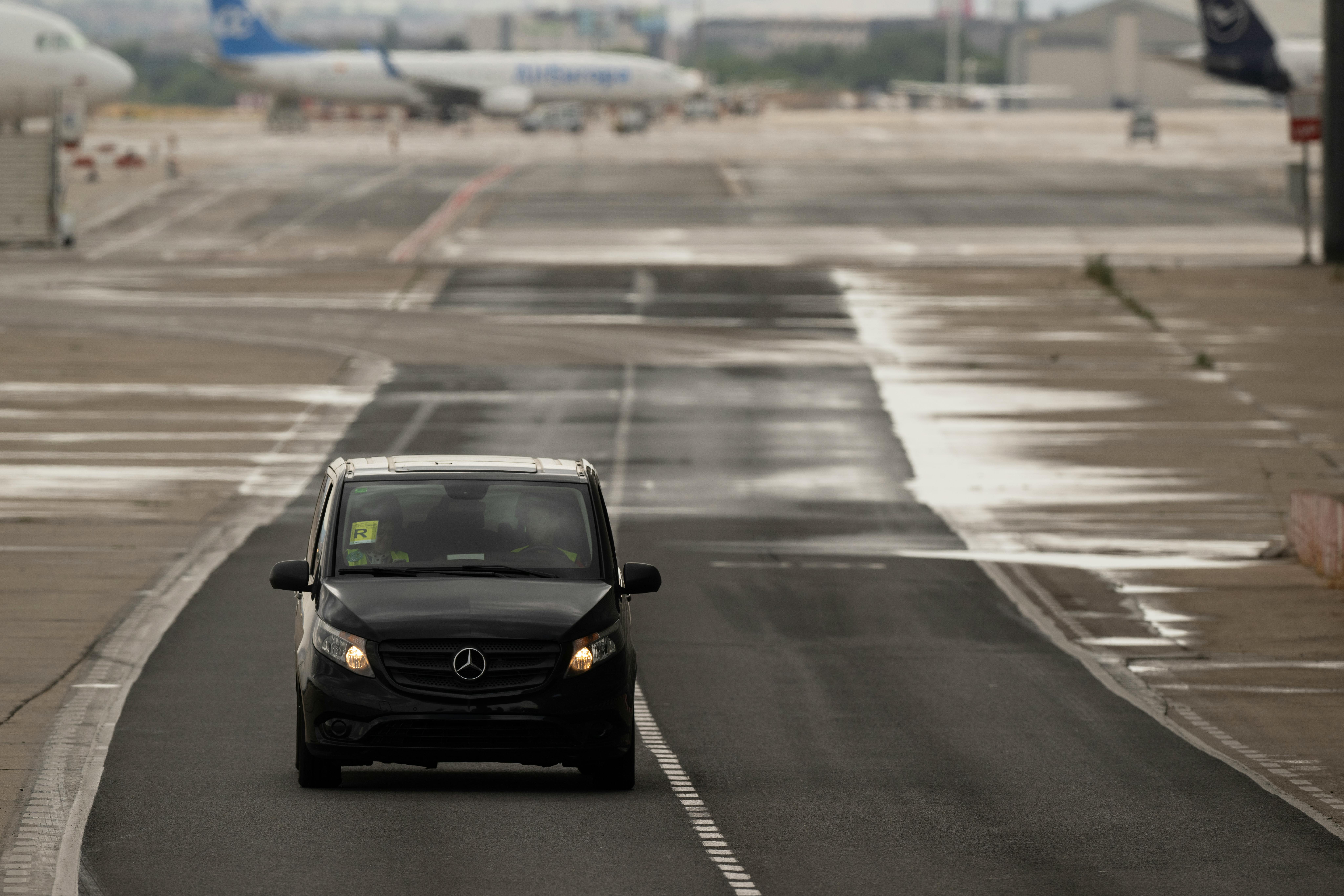 A small car driving on a wet runway · Free Stock Photo