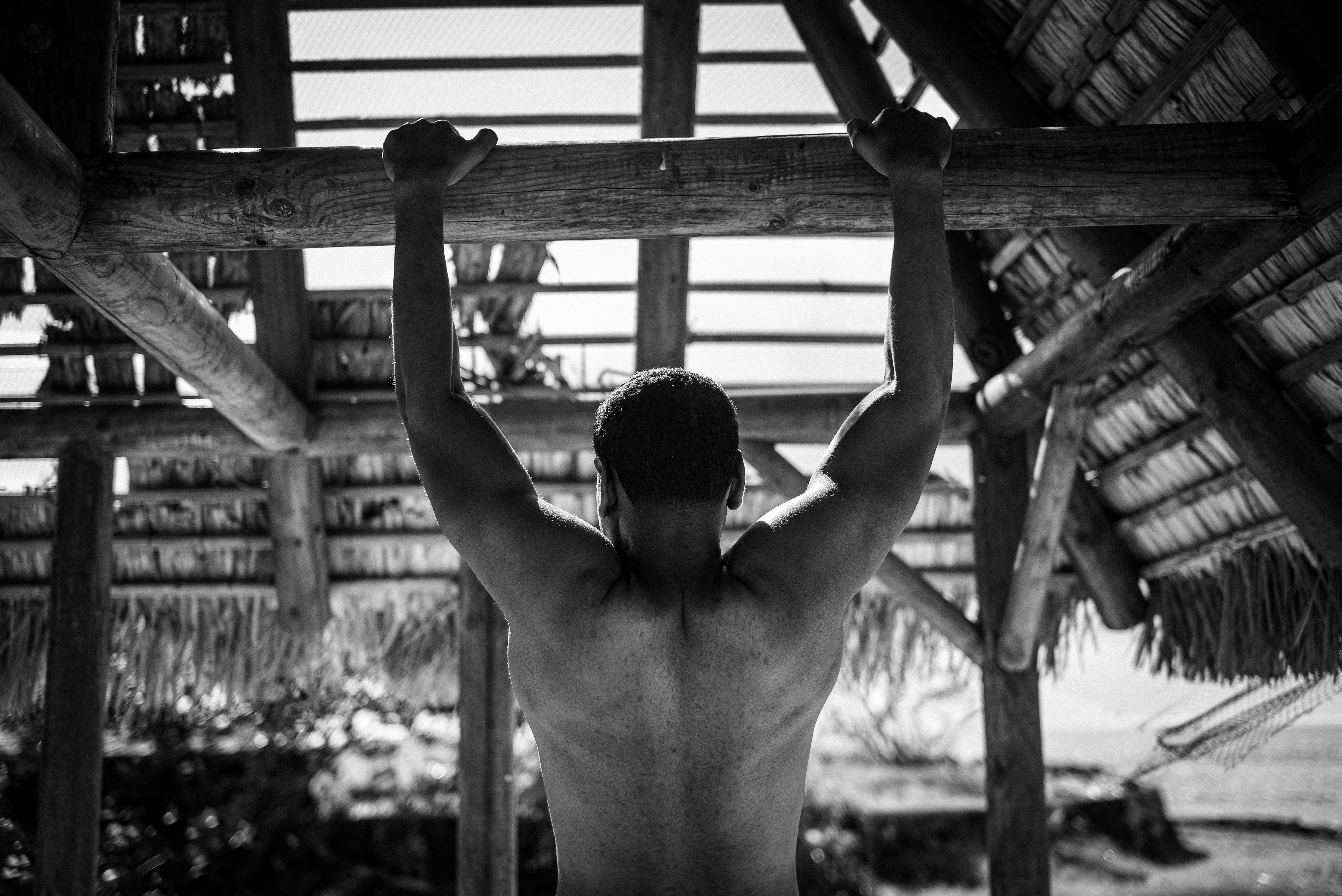 A man doing pull ups in a hut · Free Stock Photo