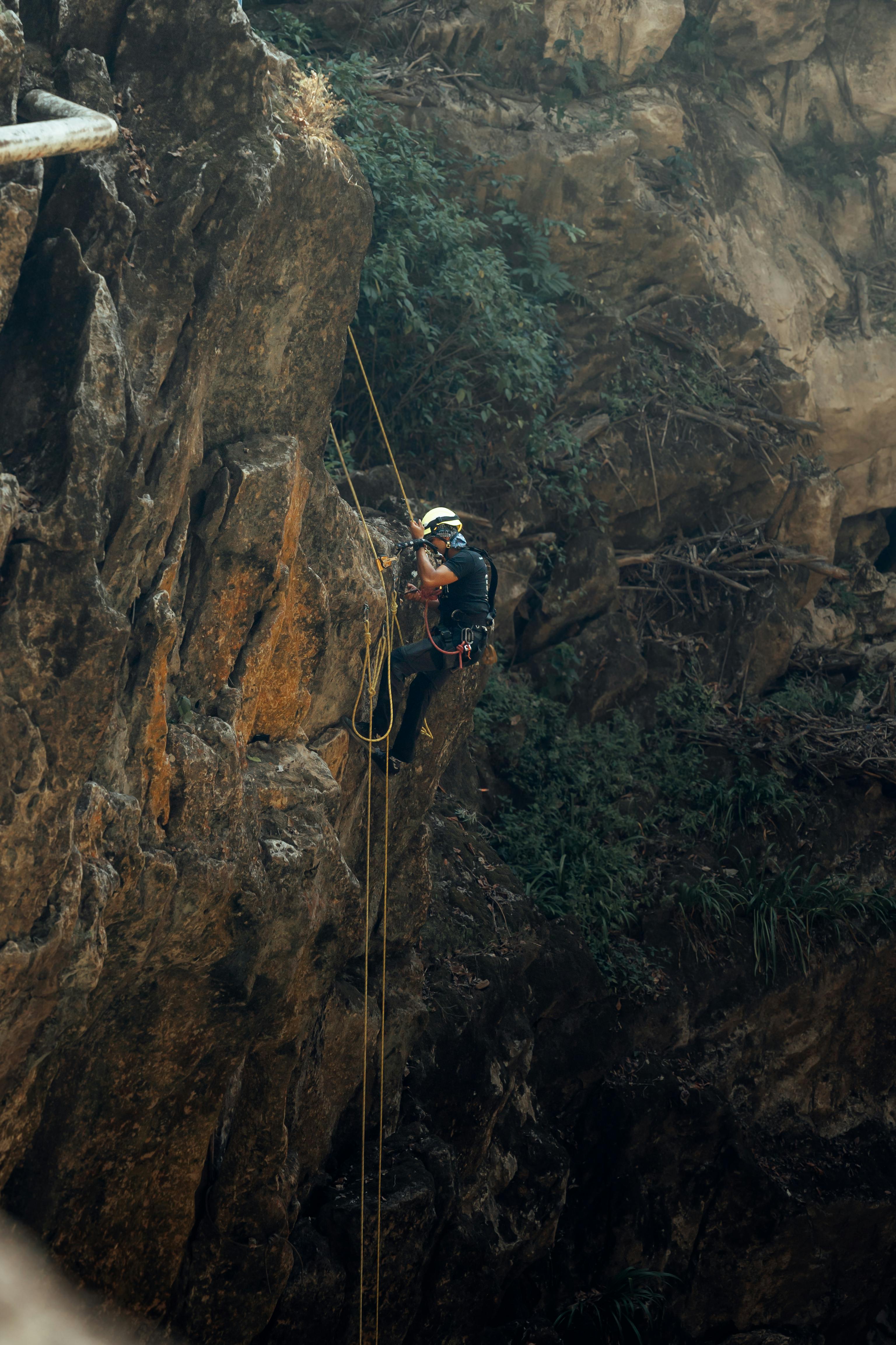 A person on a rope climbing up a cliff · Free Stock Photo
