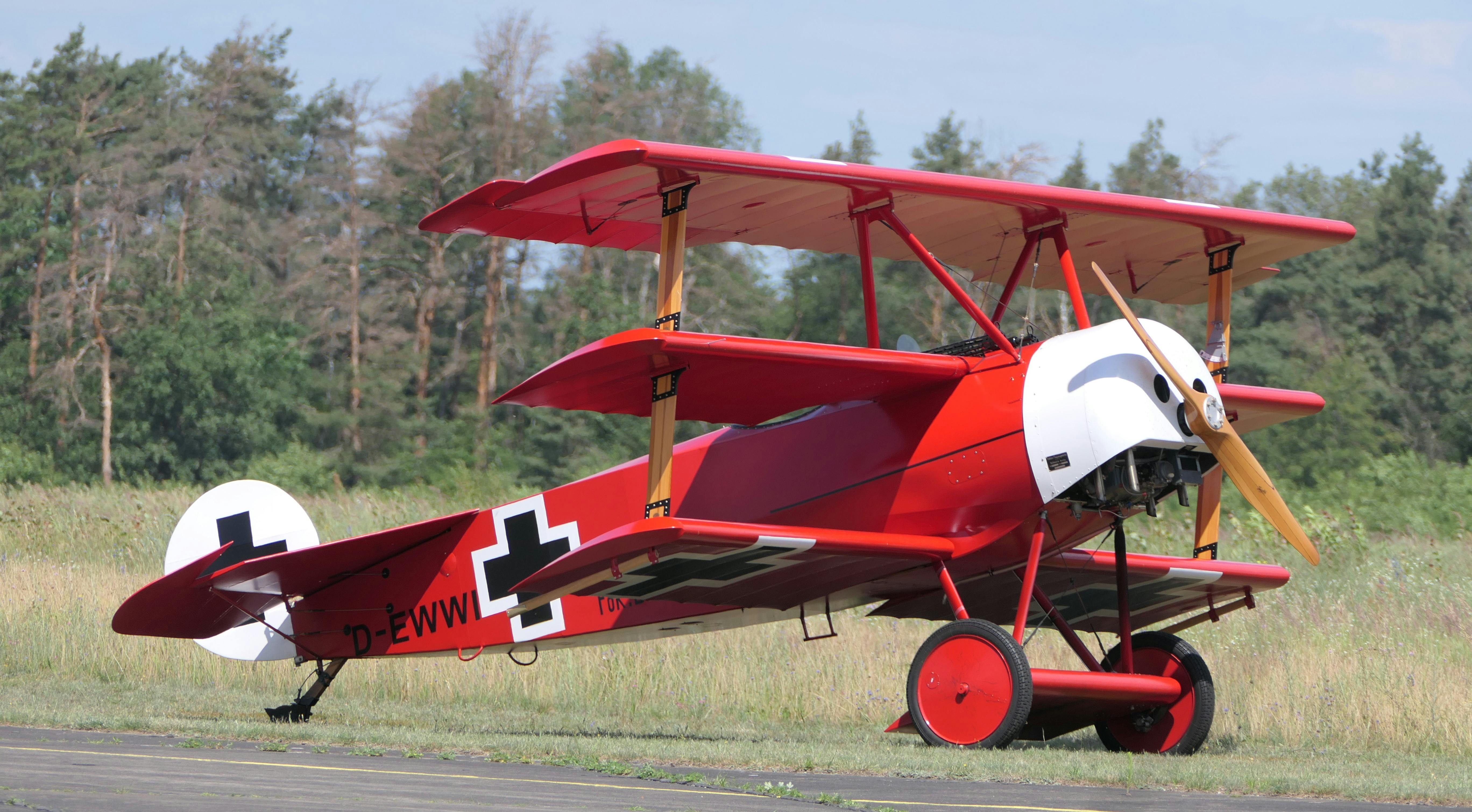 A red and white biplane sitting on a runway · Free Stock Photo