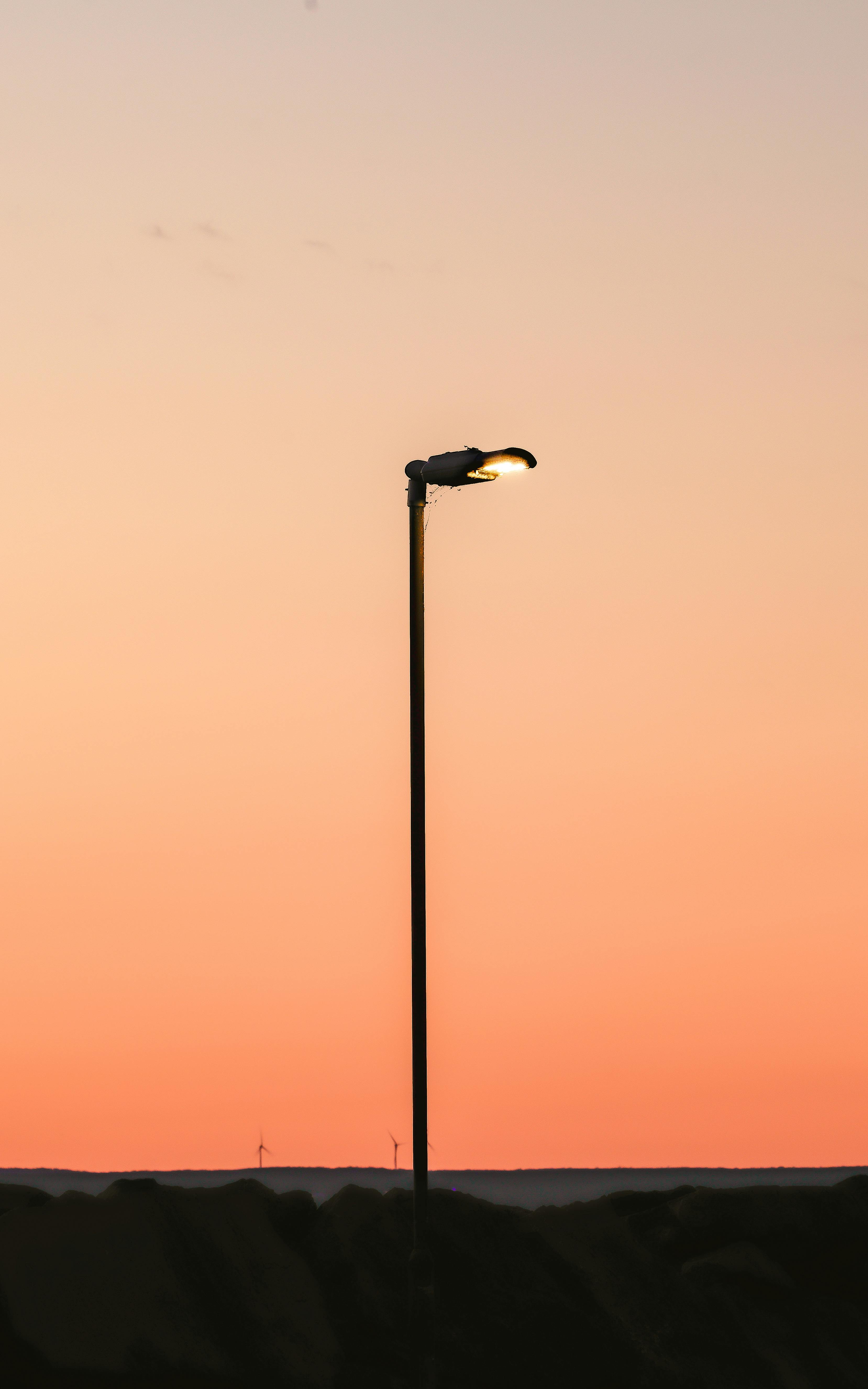 A street light is silhouetted against a sunset · Free Stock Photo