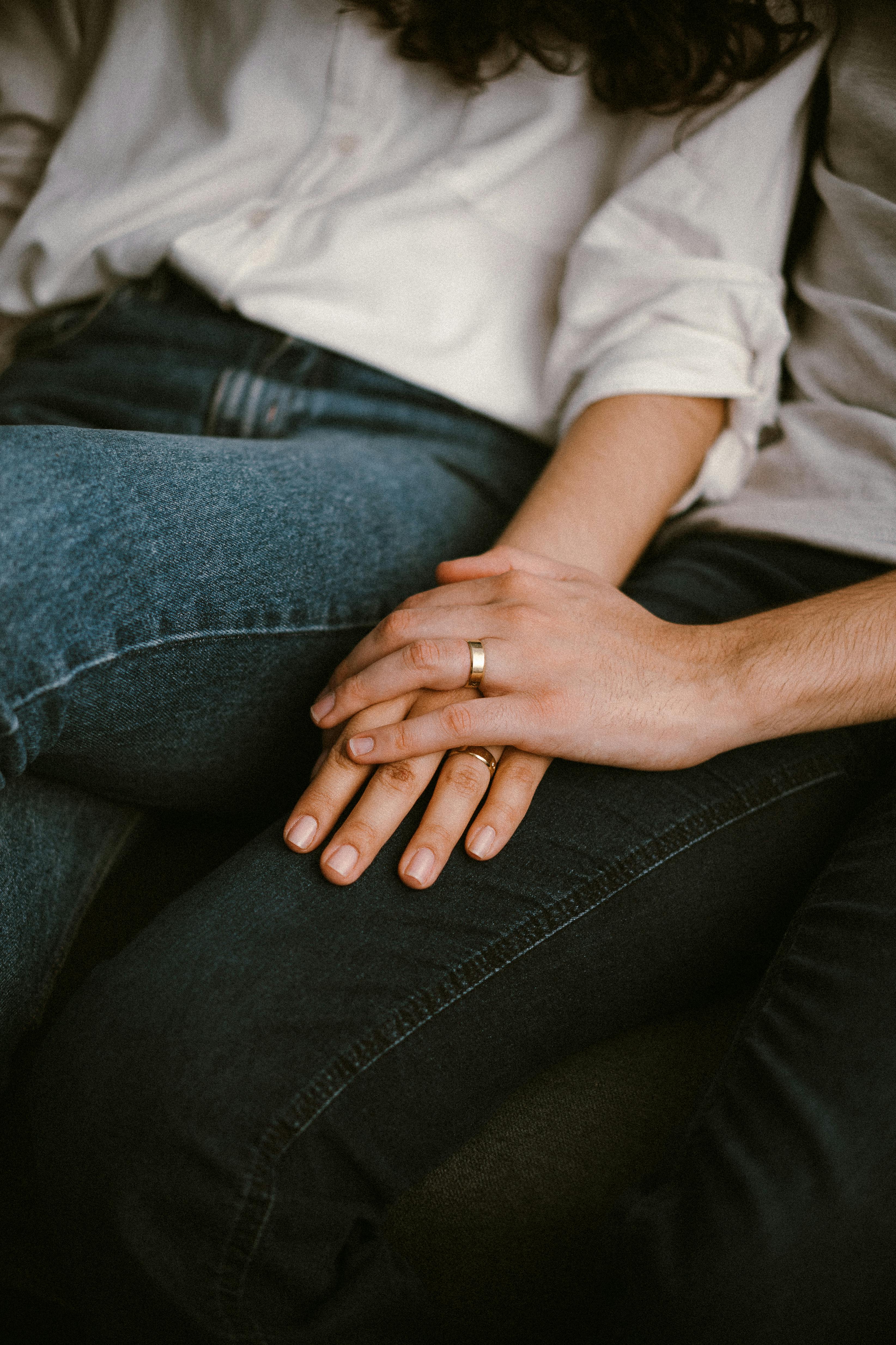 Hands Wearing Wedding Rings Resting on Mans Lap · Free Stock Photo