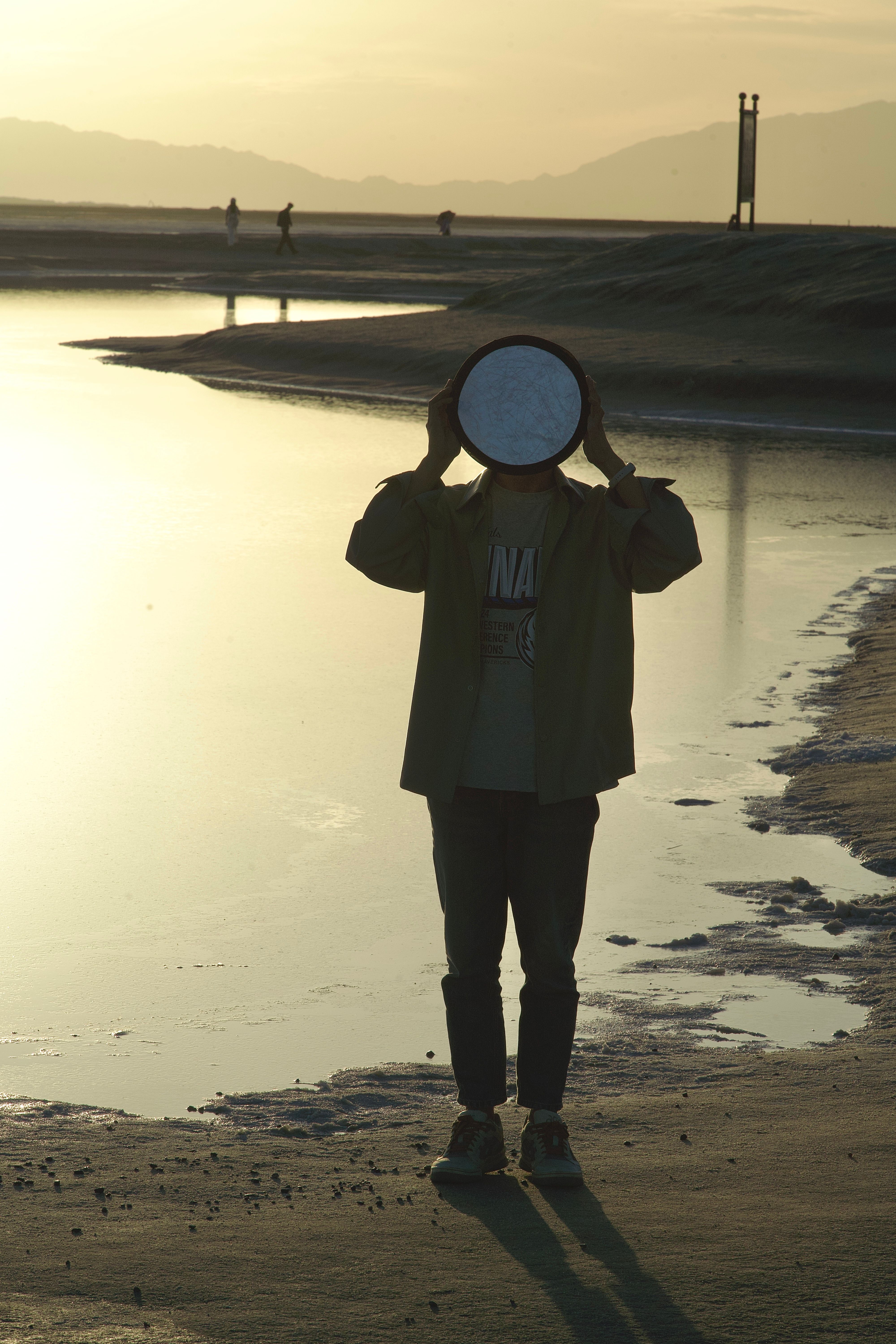 Person Standing with Mirror on Lakeshore at Sunset · Free Stock Photo