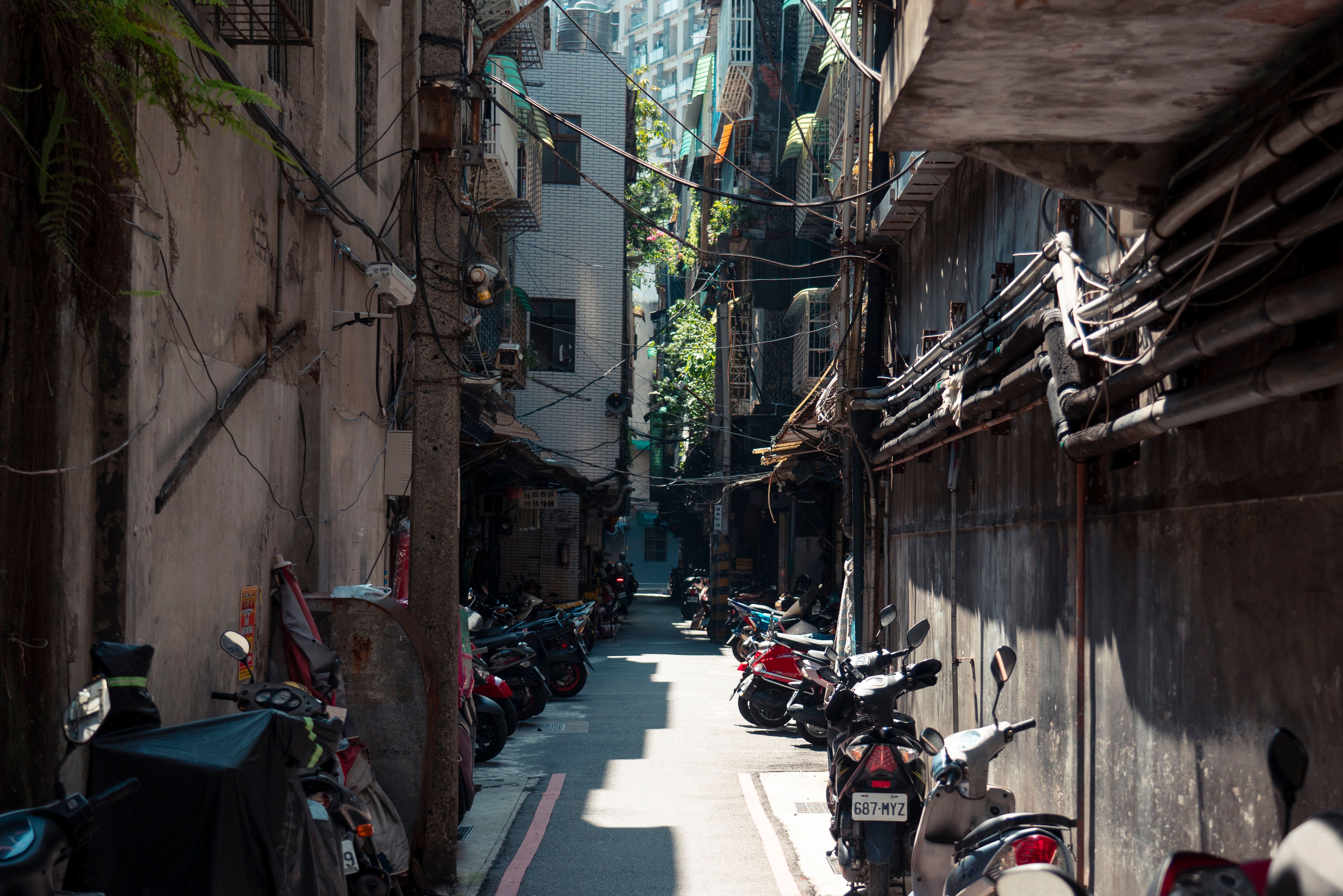 A narrow alley with motorcycles parked on the side · Free Stock Photo