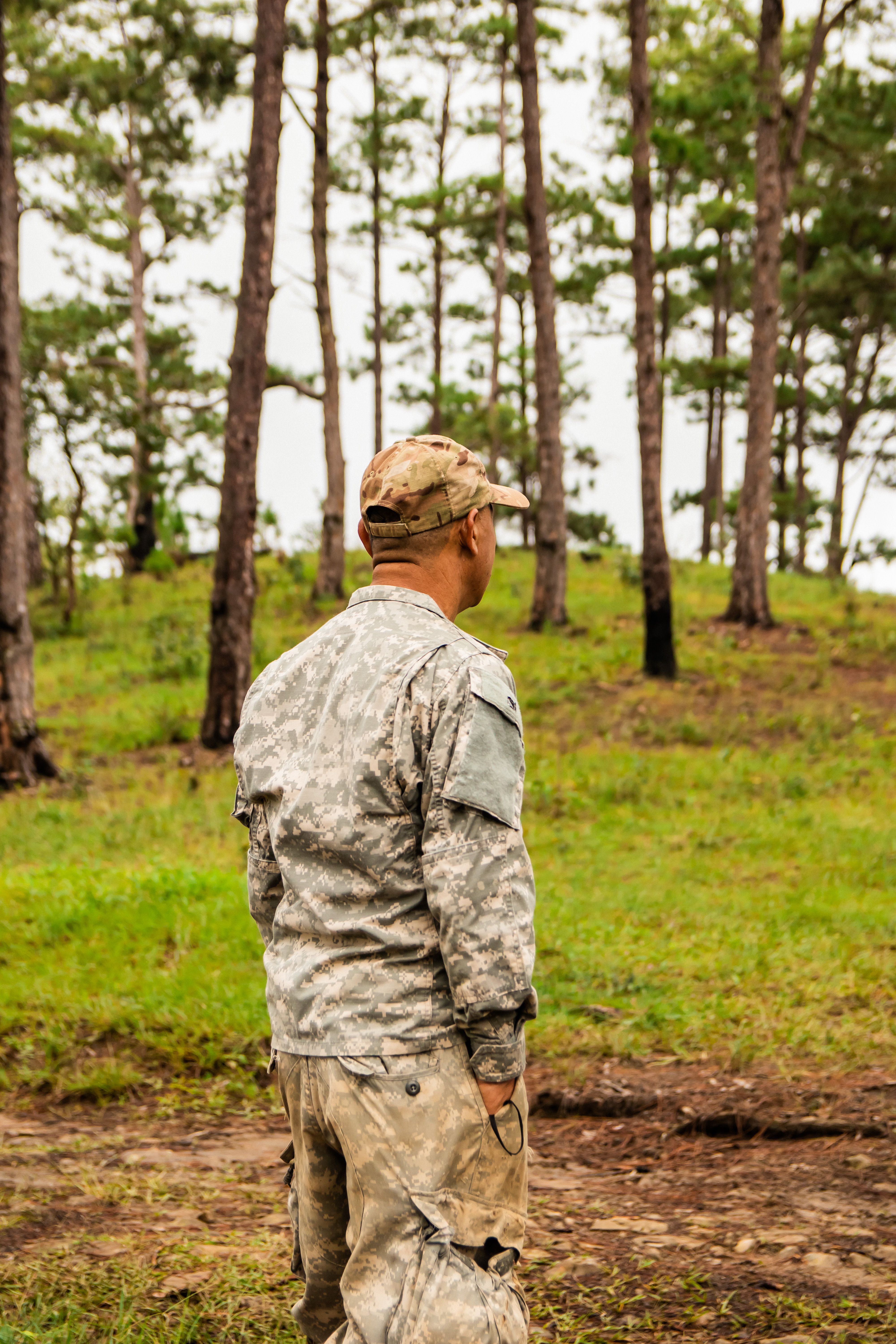 A soldier in uniform stands in front of a tree · Free Stock Photo