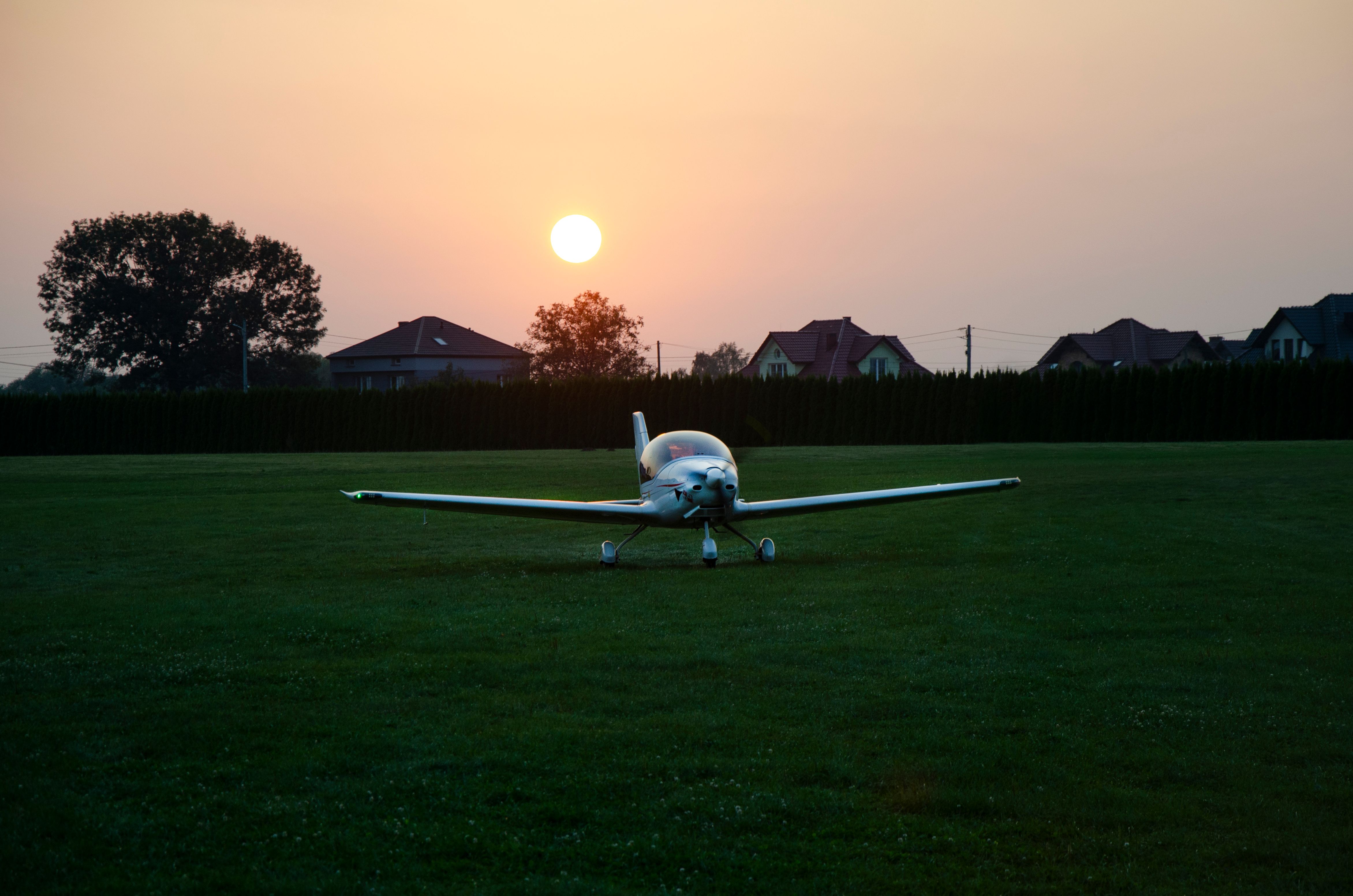 A small airplane sitting on a grassy field at sunset · Free Stock Photo