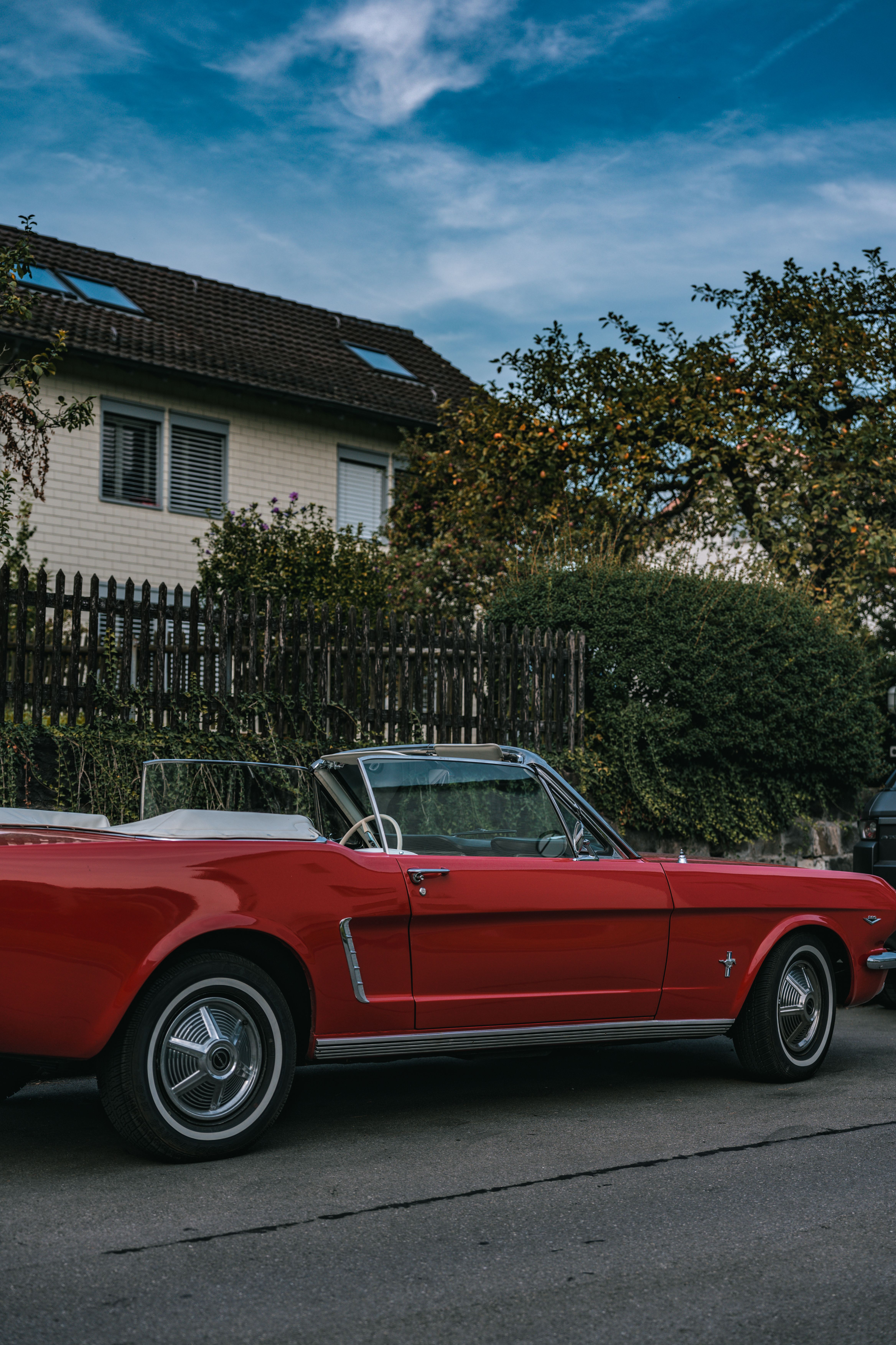 A red mustang convertible parked in front of a house · Free Stock Photo