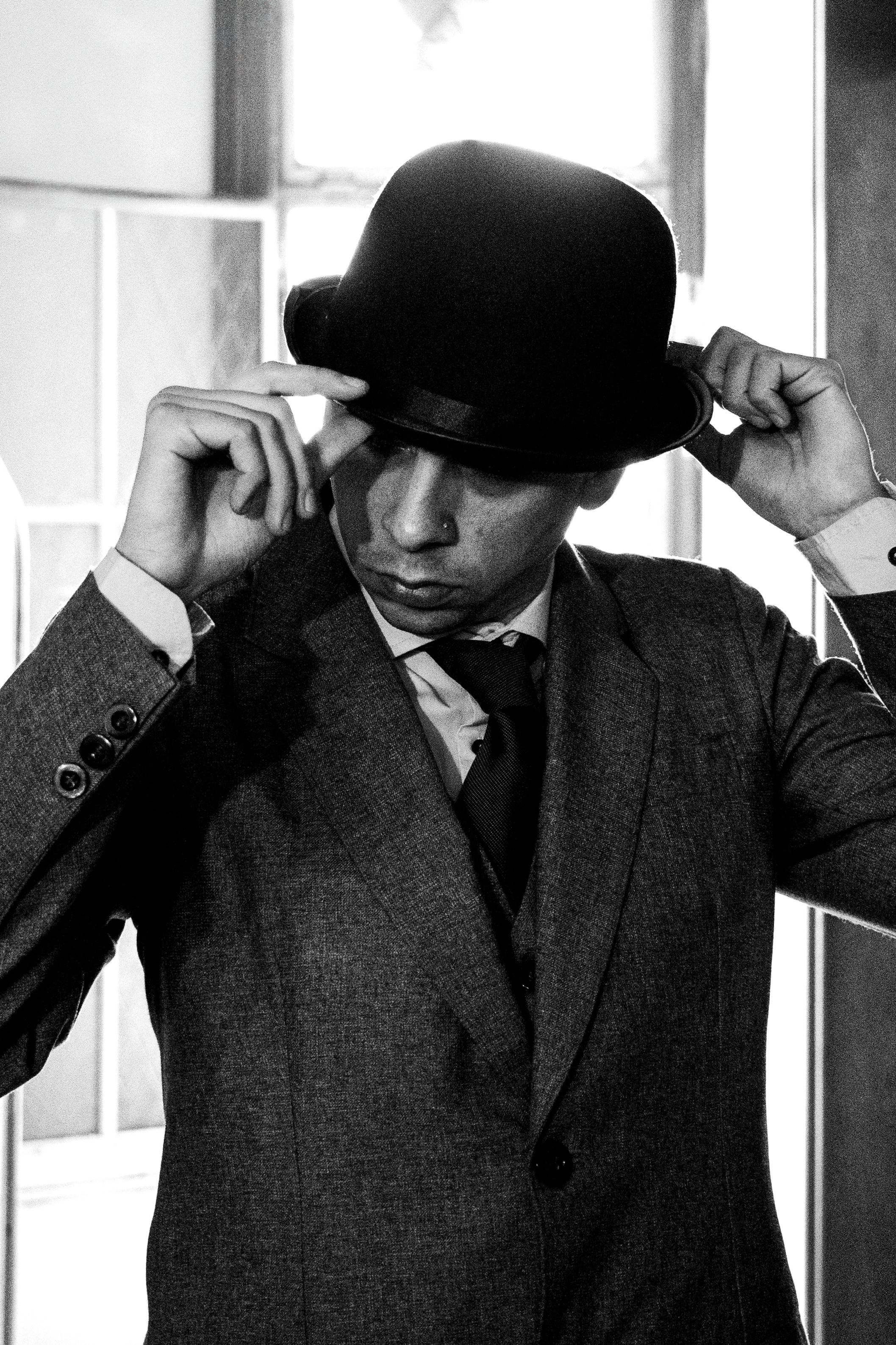 A man in a suit and hat adjusting his hat · Free Stock Photo