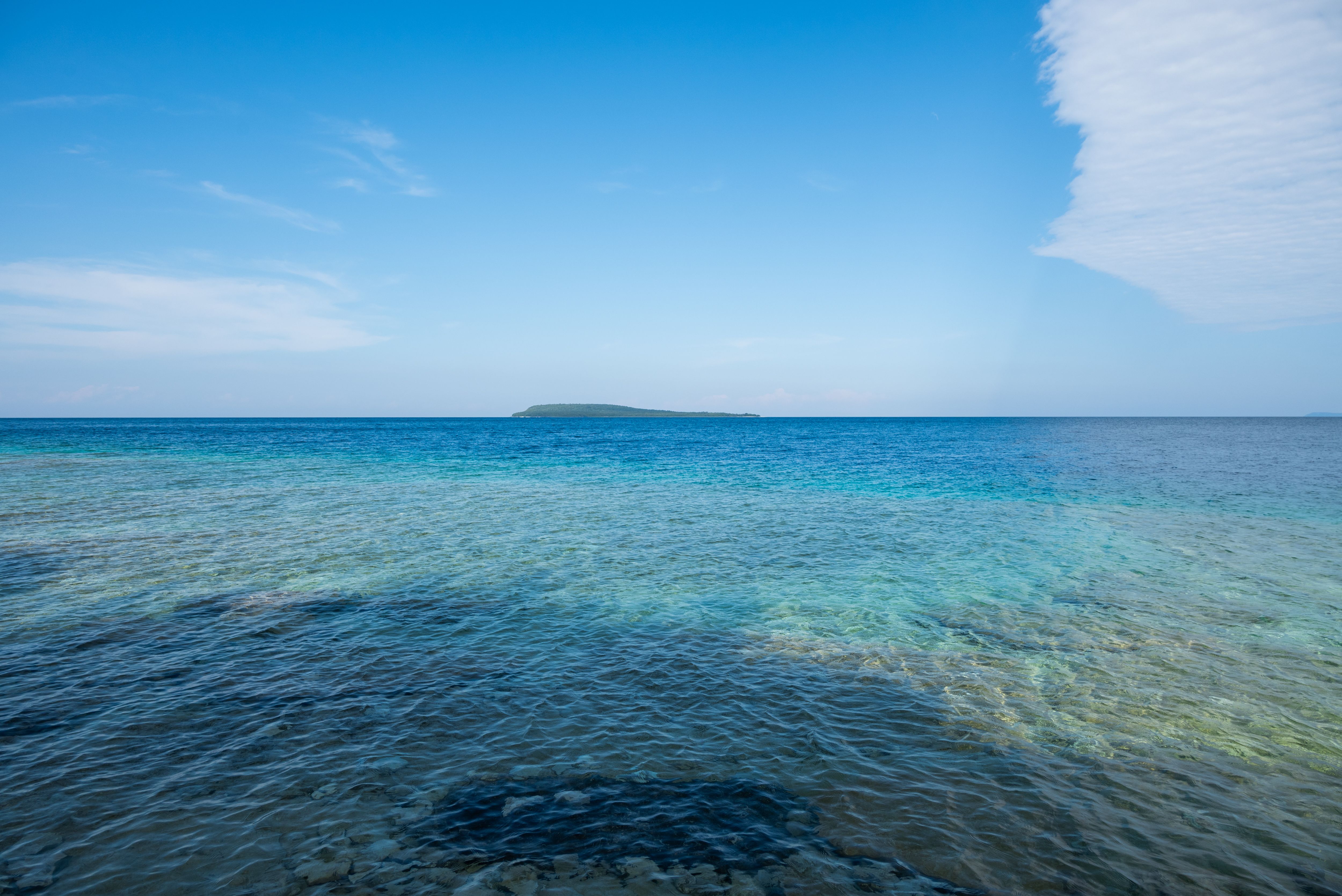 A clear blue ocean with a small island in the distance · Free Stock Photo