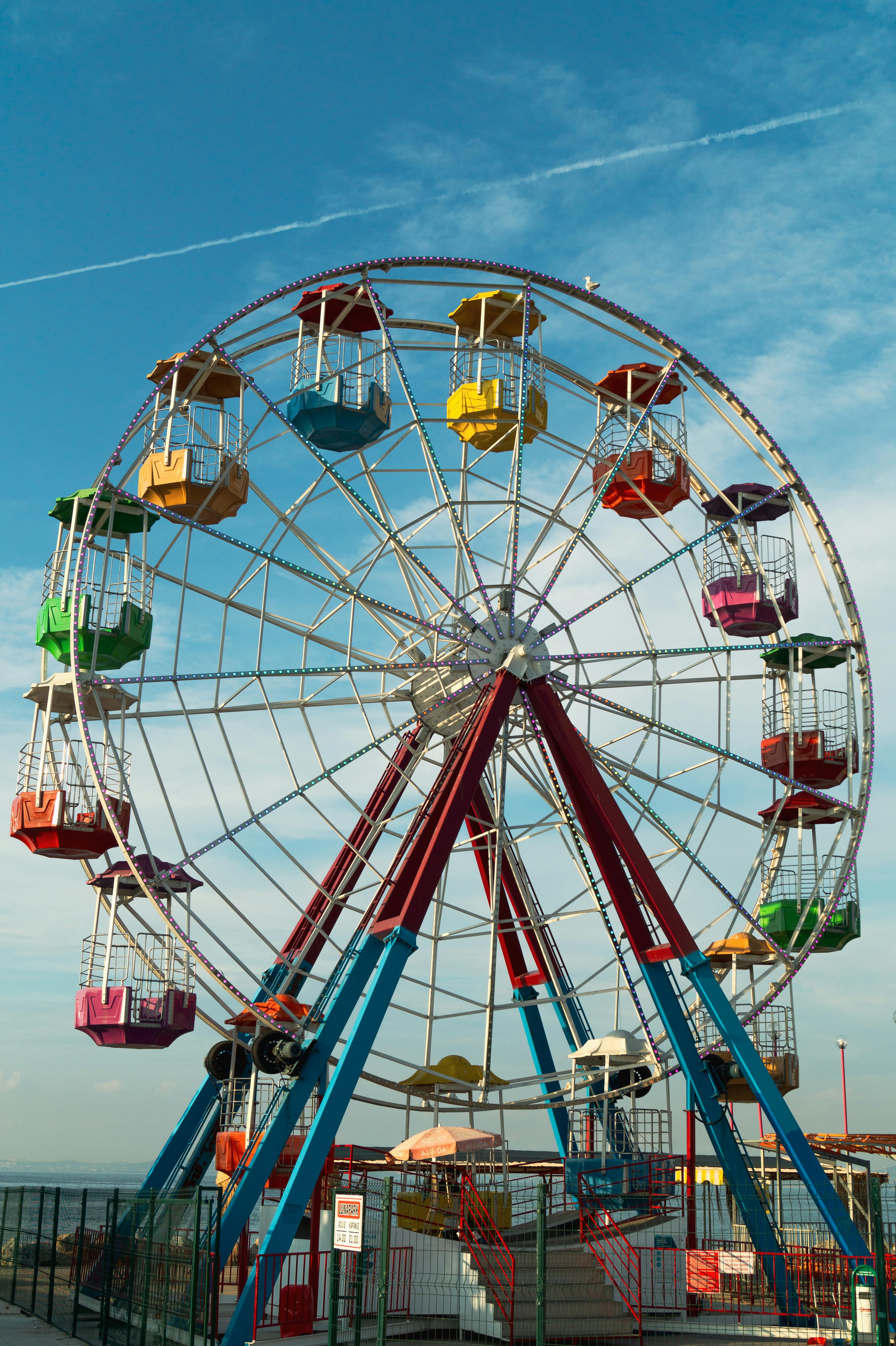 A ferris wheel with colorful seats and a blue sky · Free Stock Photo