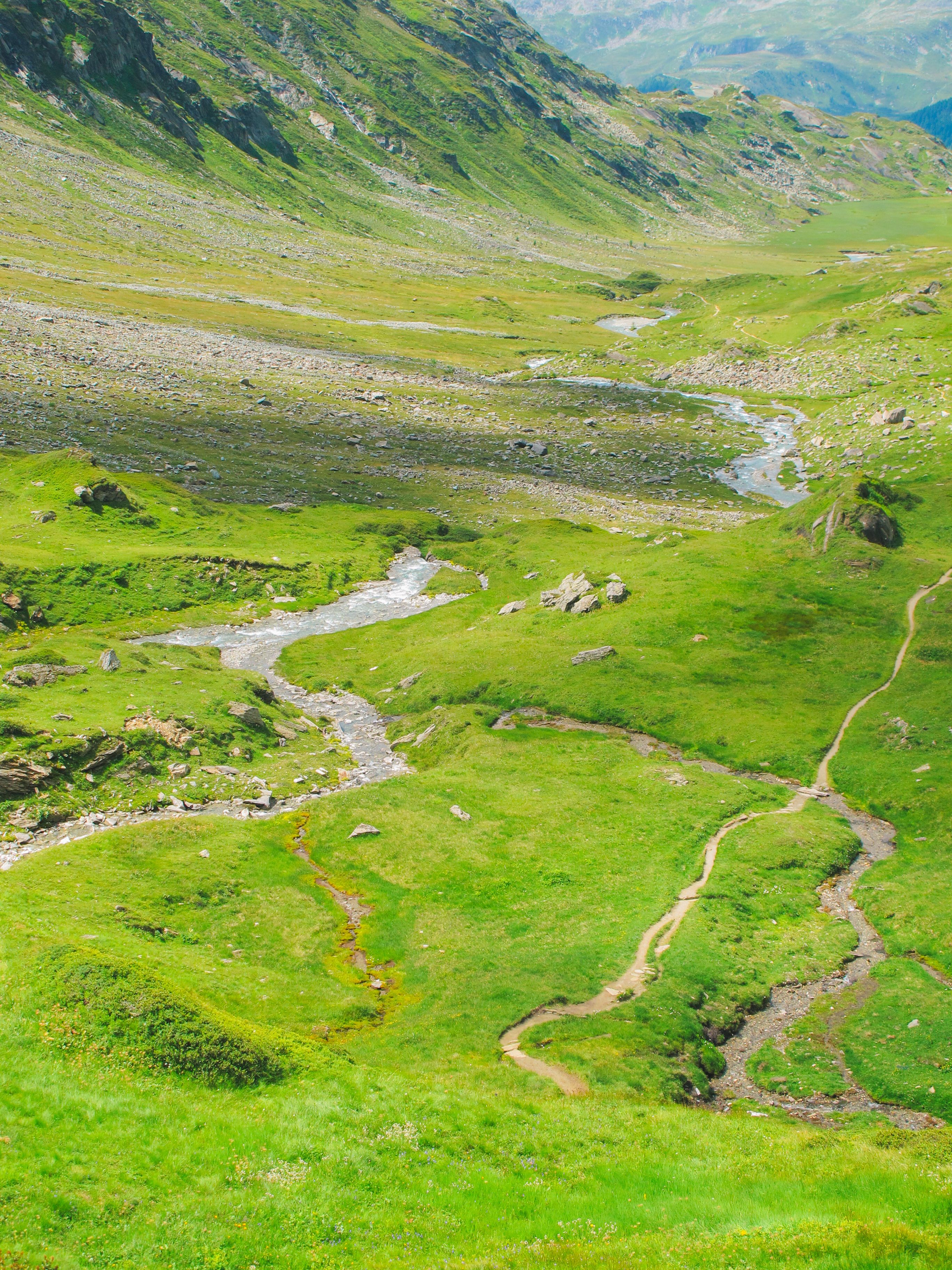 A green valley with a stream running through it · Free Stock Photo
