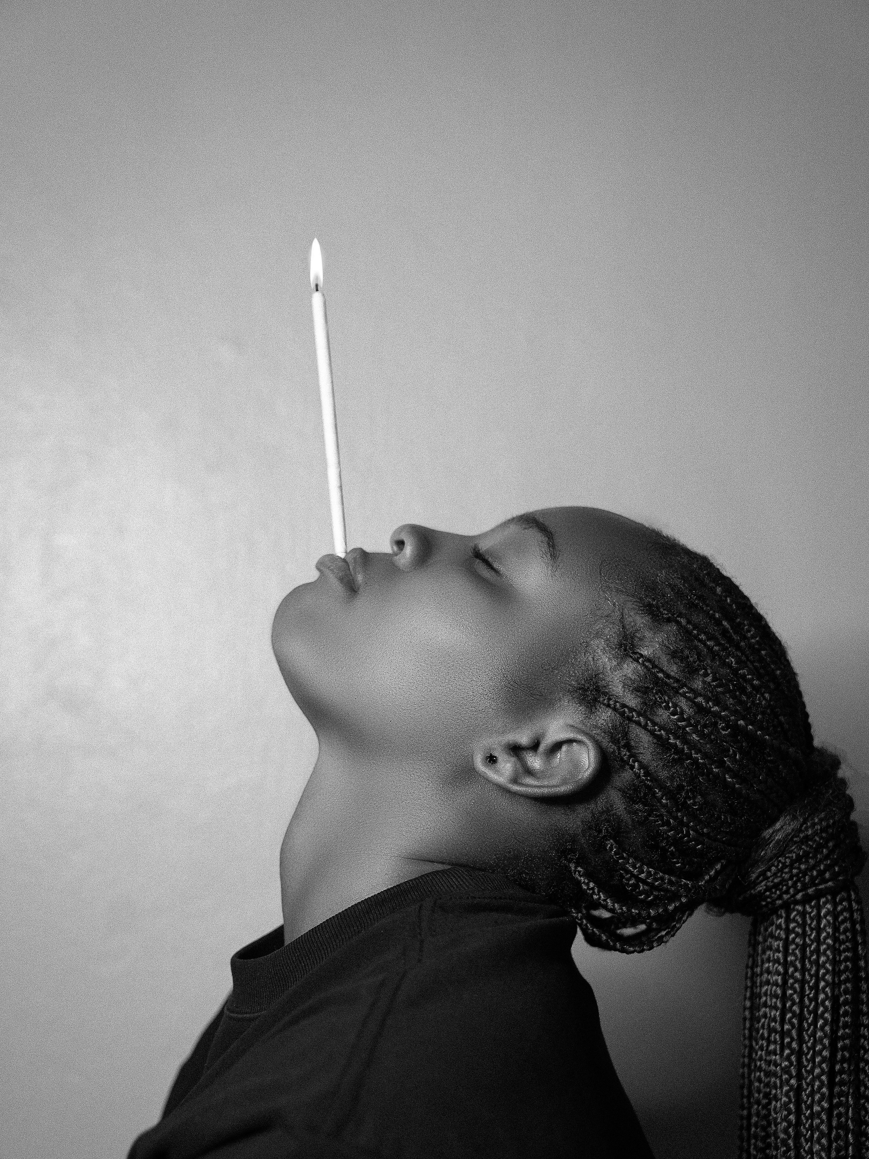 A woman with braids holding a lit candle · Free Stock Photo