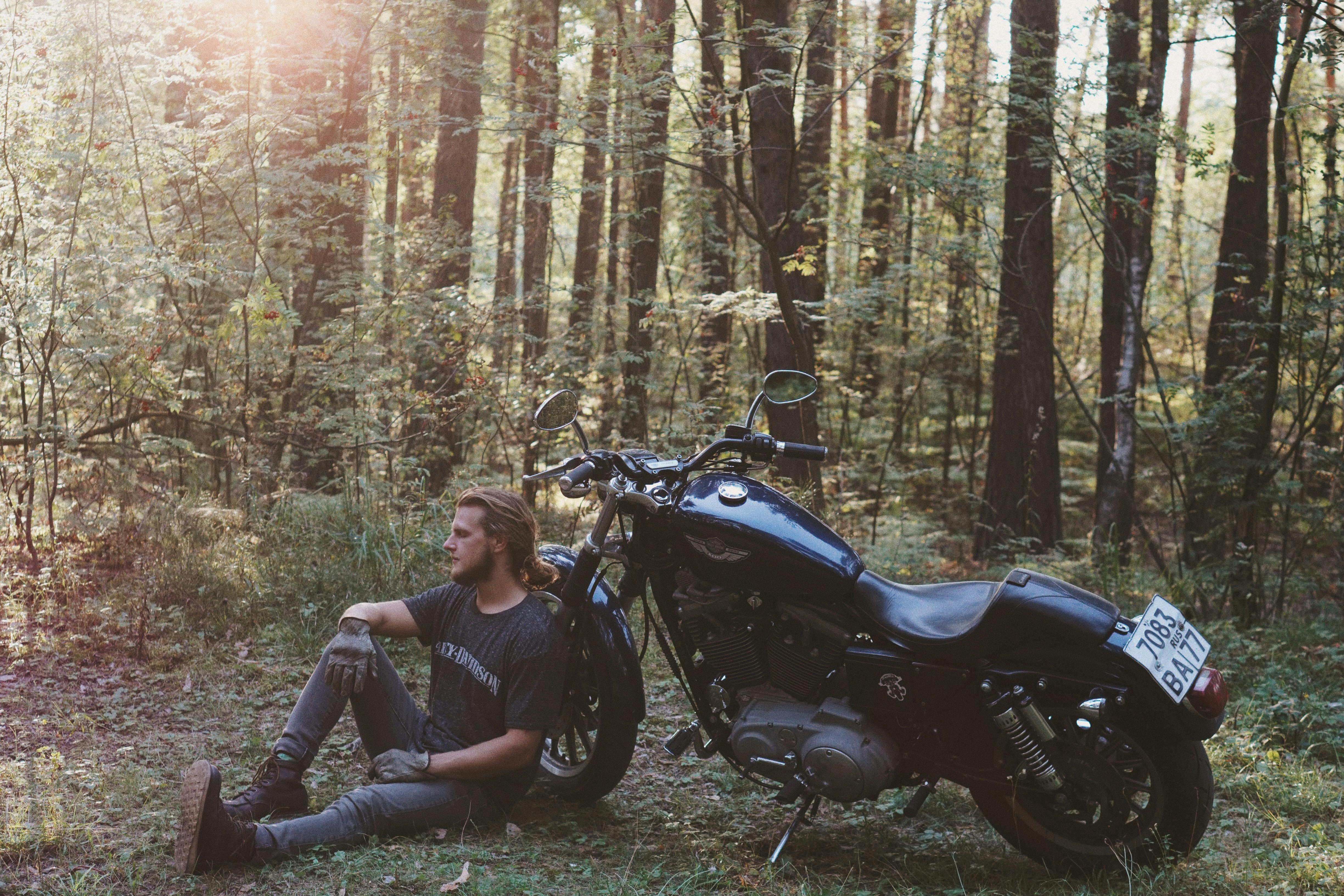 Man Sitting on the Ground Leaning Back on Parked Motorcycle · Free ...