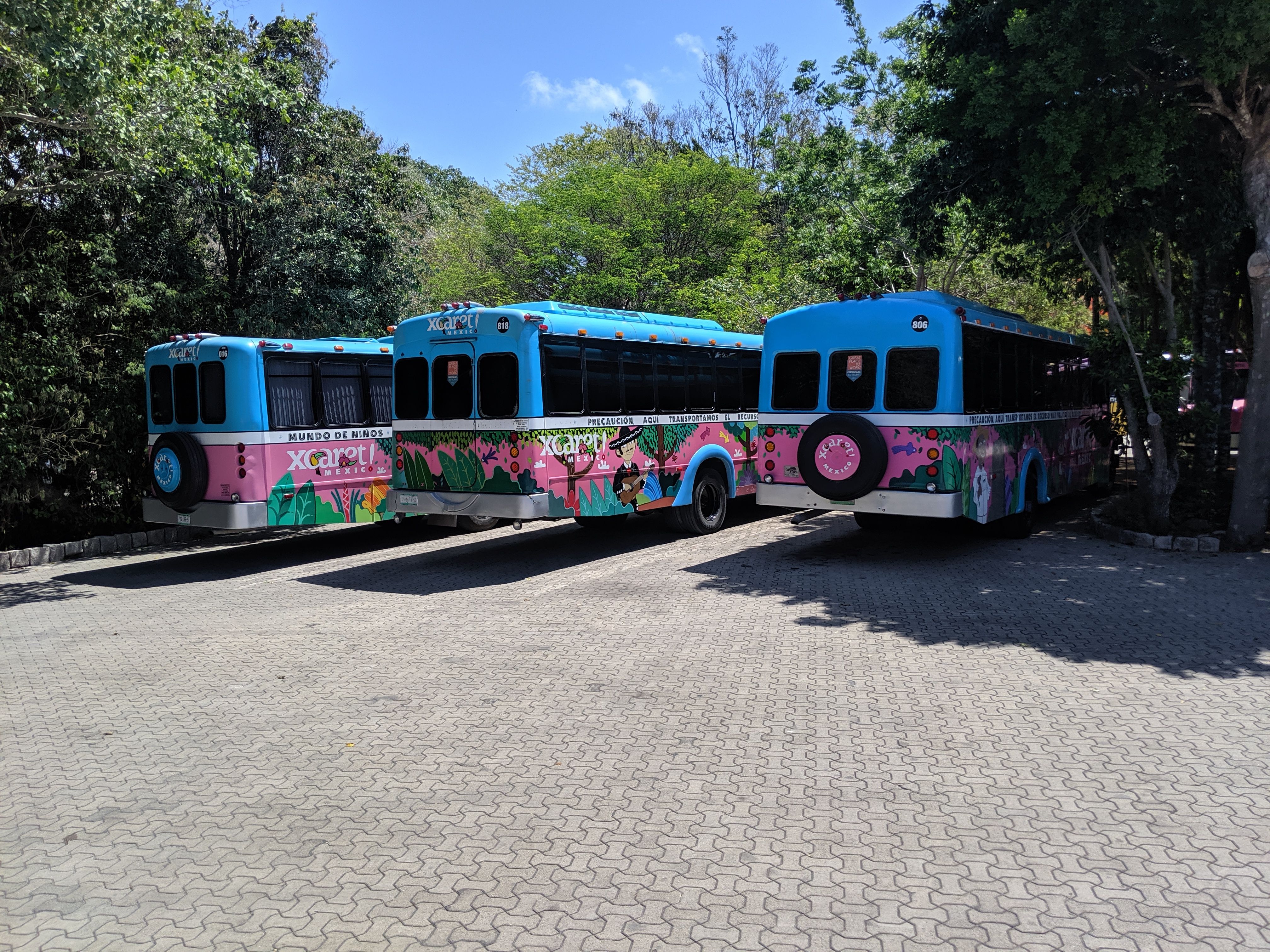 Three buses painted with colorful designs parked in a parking lot ...