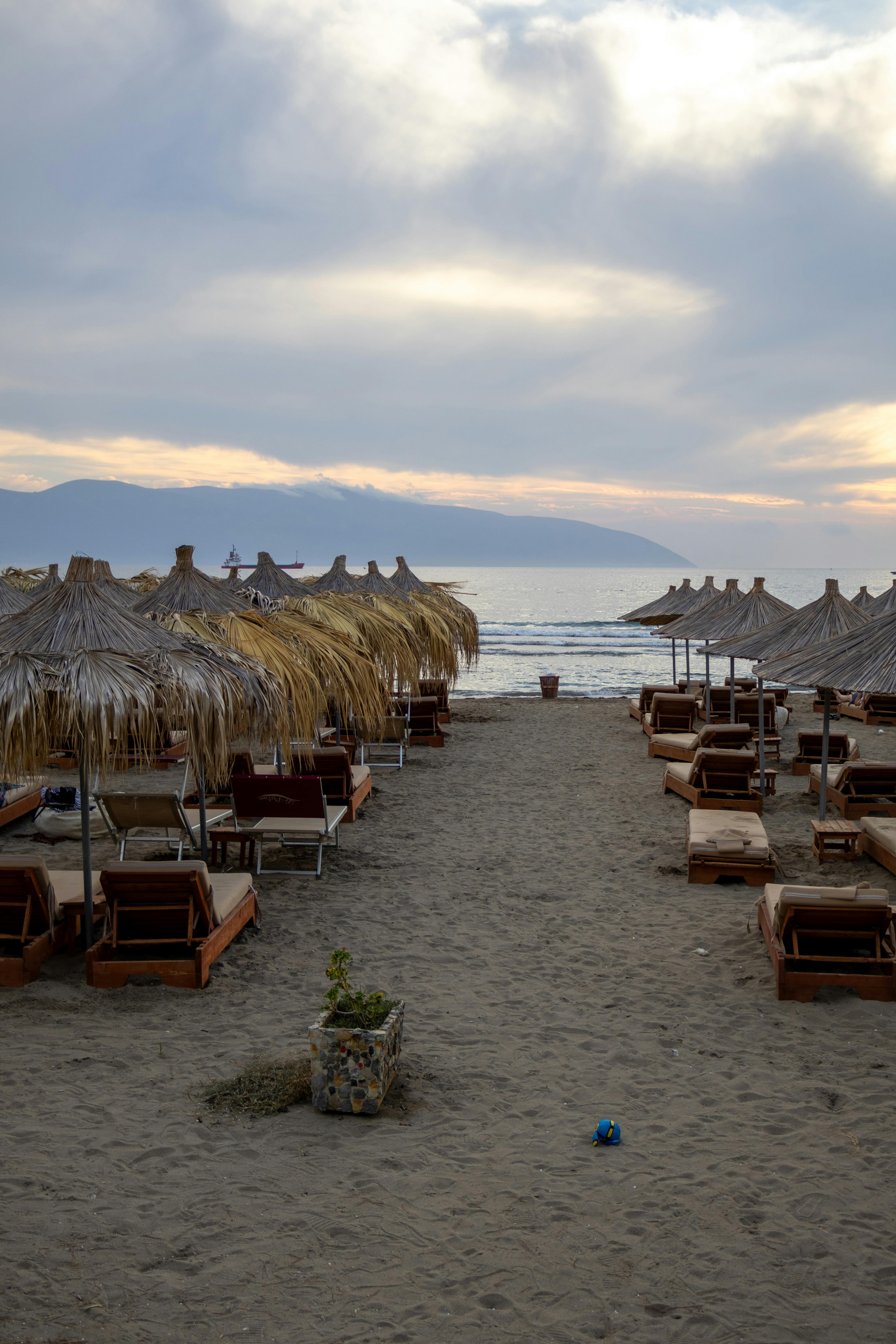 Sunset at Vlora Beach with Straw Umbrellas · Free Stock Photo