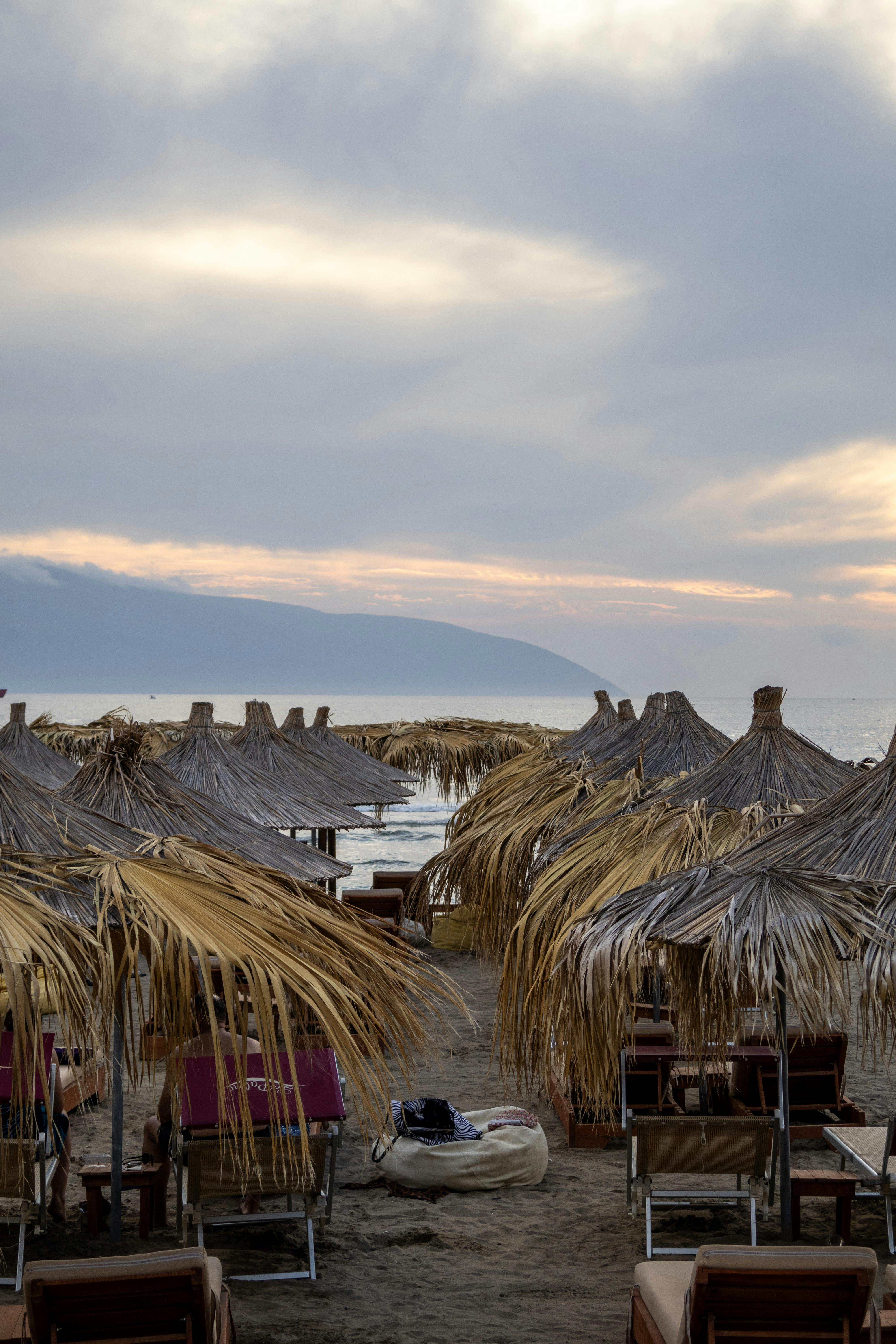 Sunset at Vlora Beach with Straw Umbrellas · Free Stock Photo