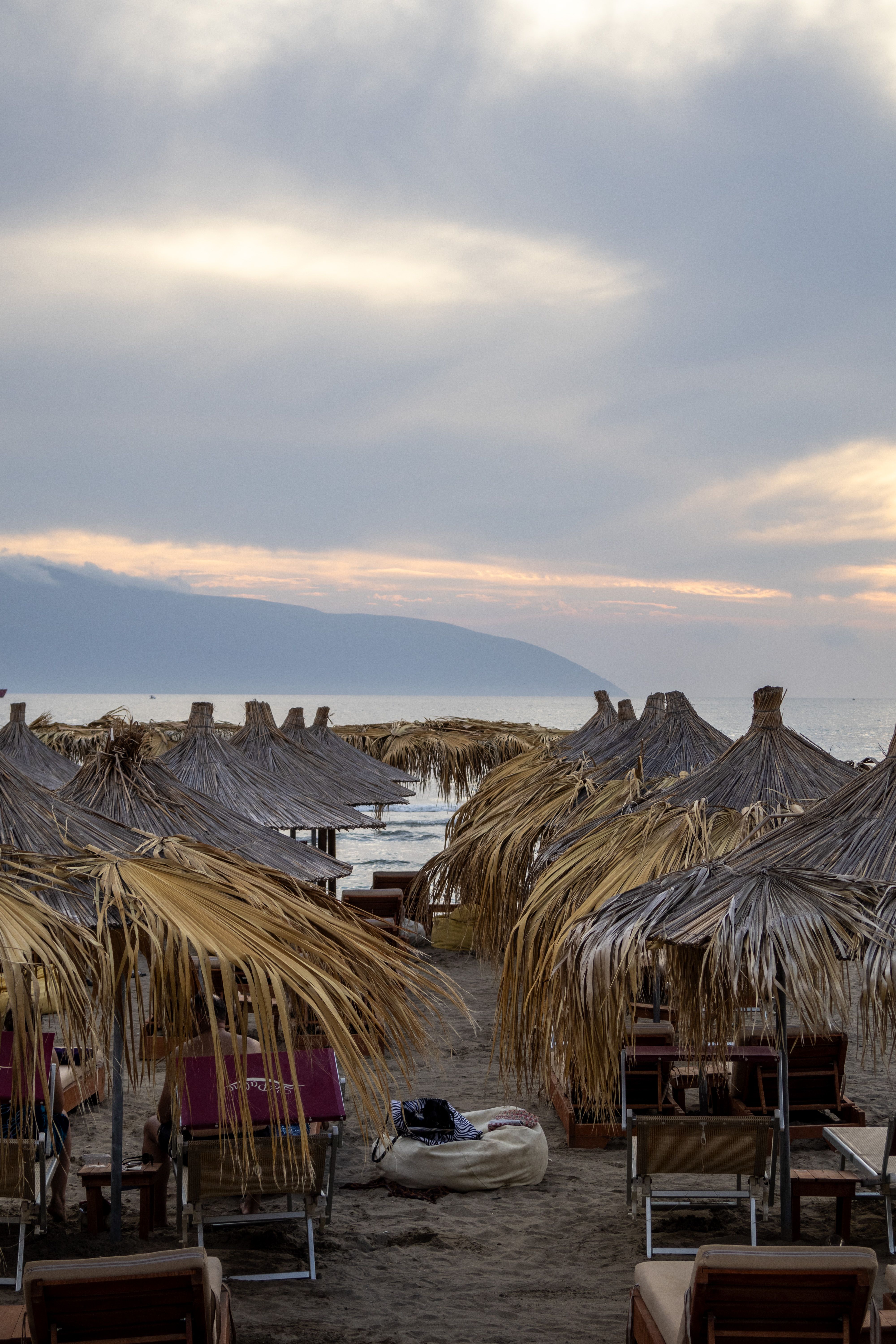 Sunset at Vlora Beach with Straw Umbrellas · Free Stock Photo