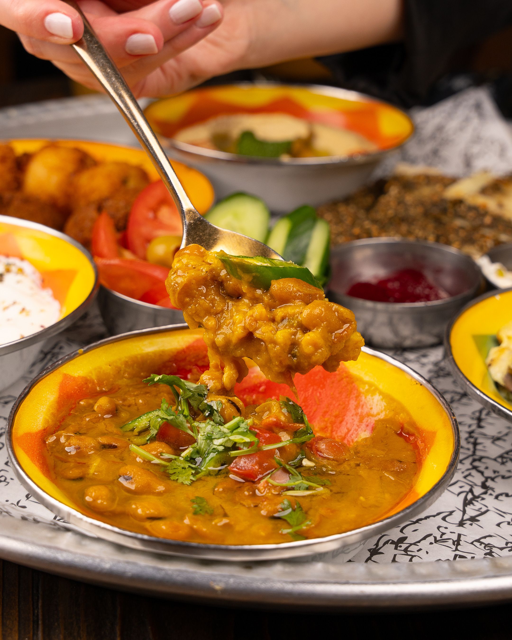 A person is holding a spoon over a plate of food · Free Stock Photo