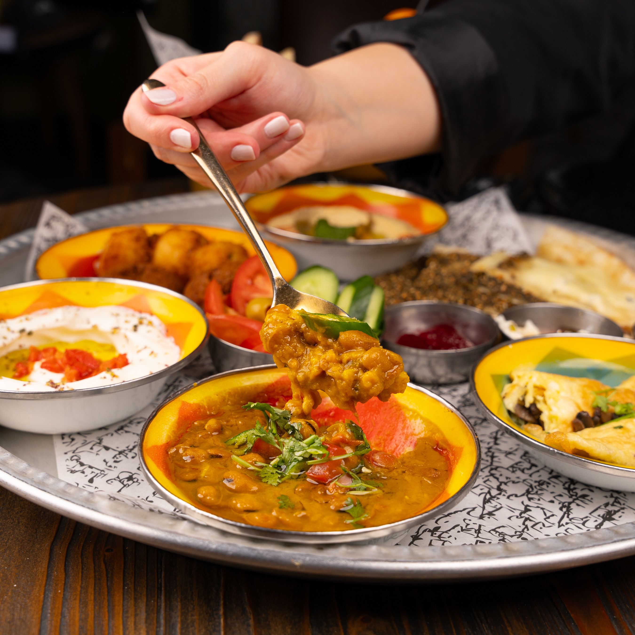 A person holding a spoon over a plate of food · Free Stock Photo