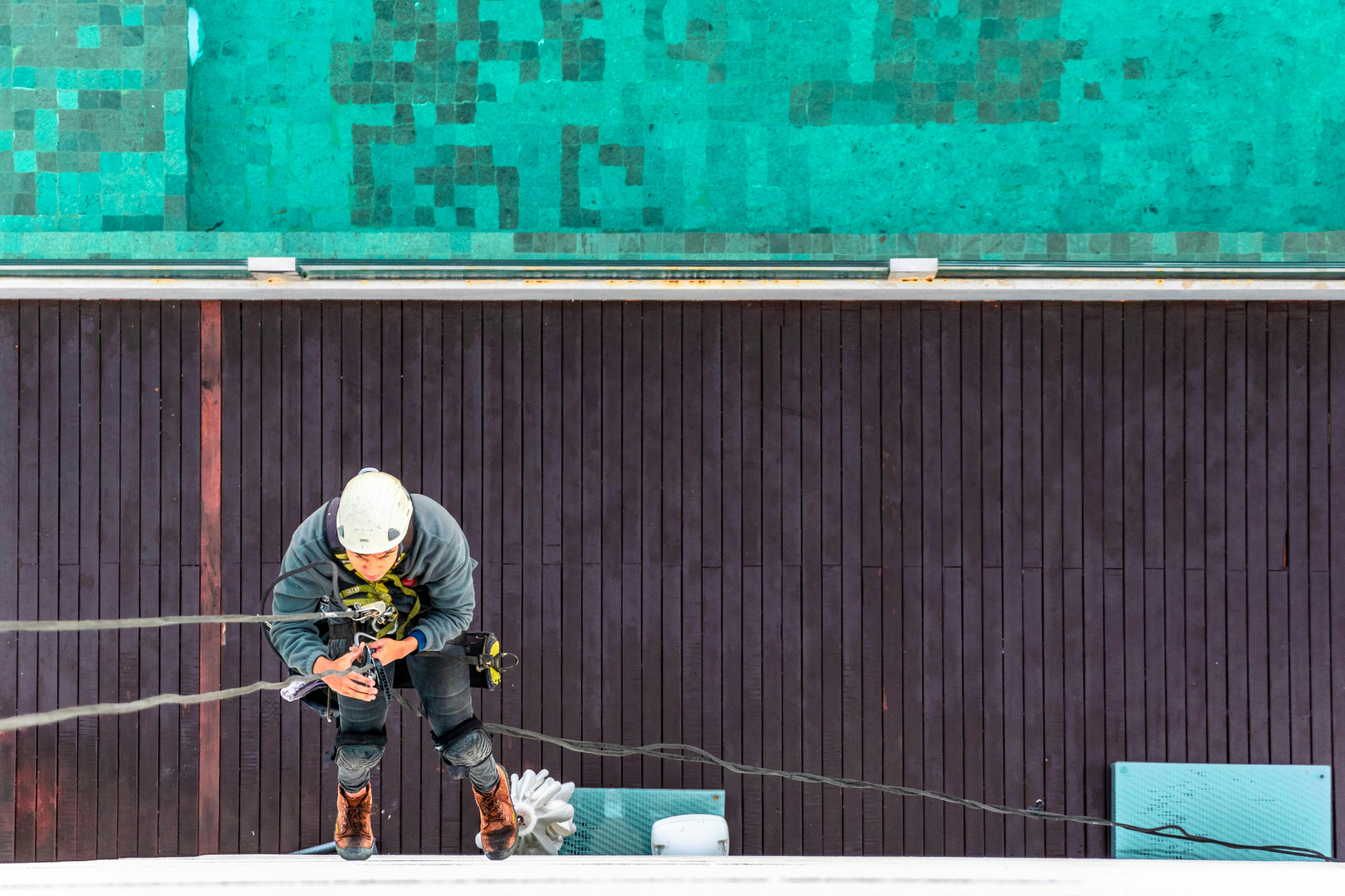 Worker Hanging on a Wall over a Swimming Pool · Free Stock Photo