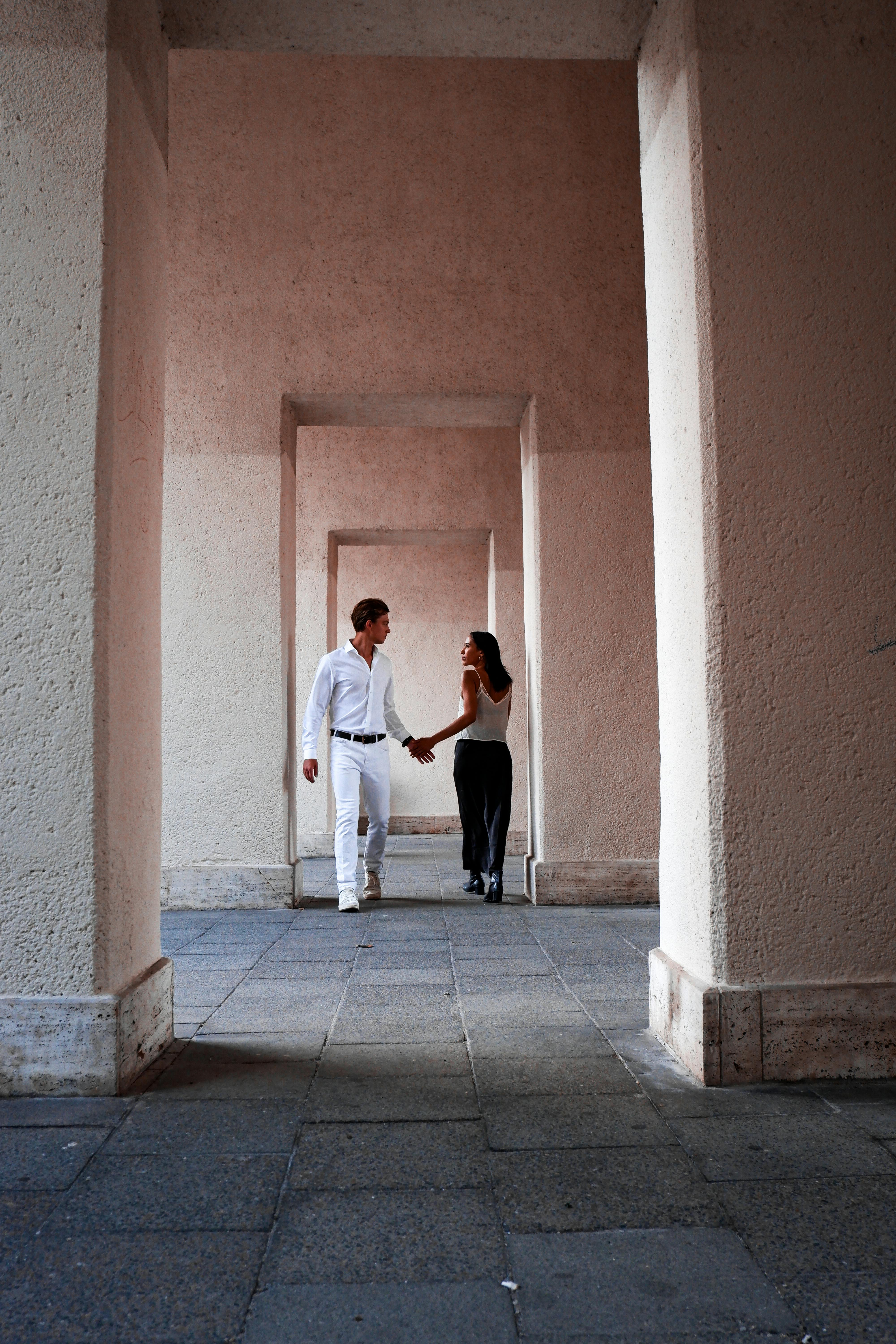 A couple holding hands in an archway · Free Stock Photo