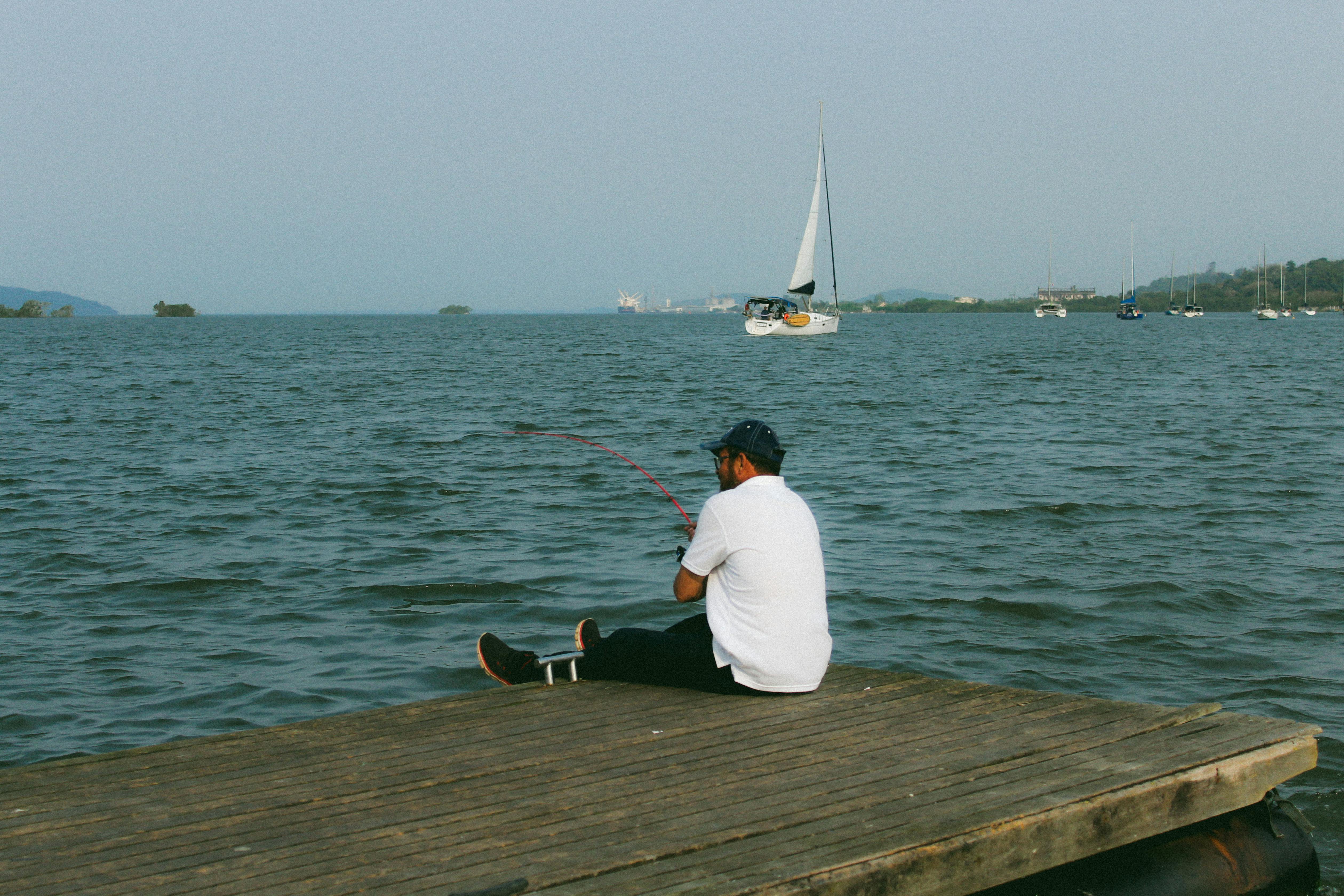 Peaceful Fishing on a Tranquil Lake Dock · Free Stock Photo