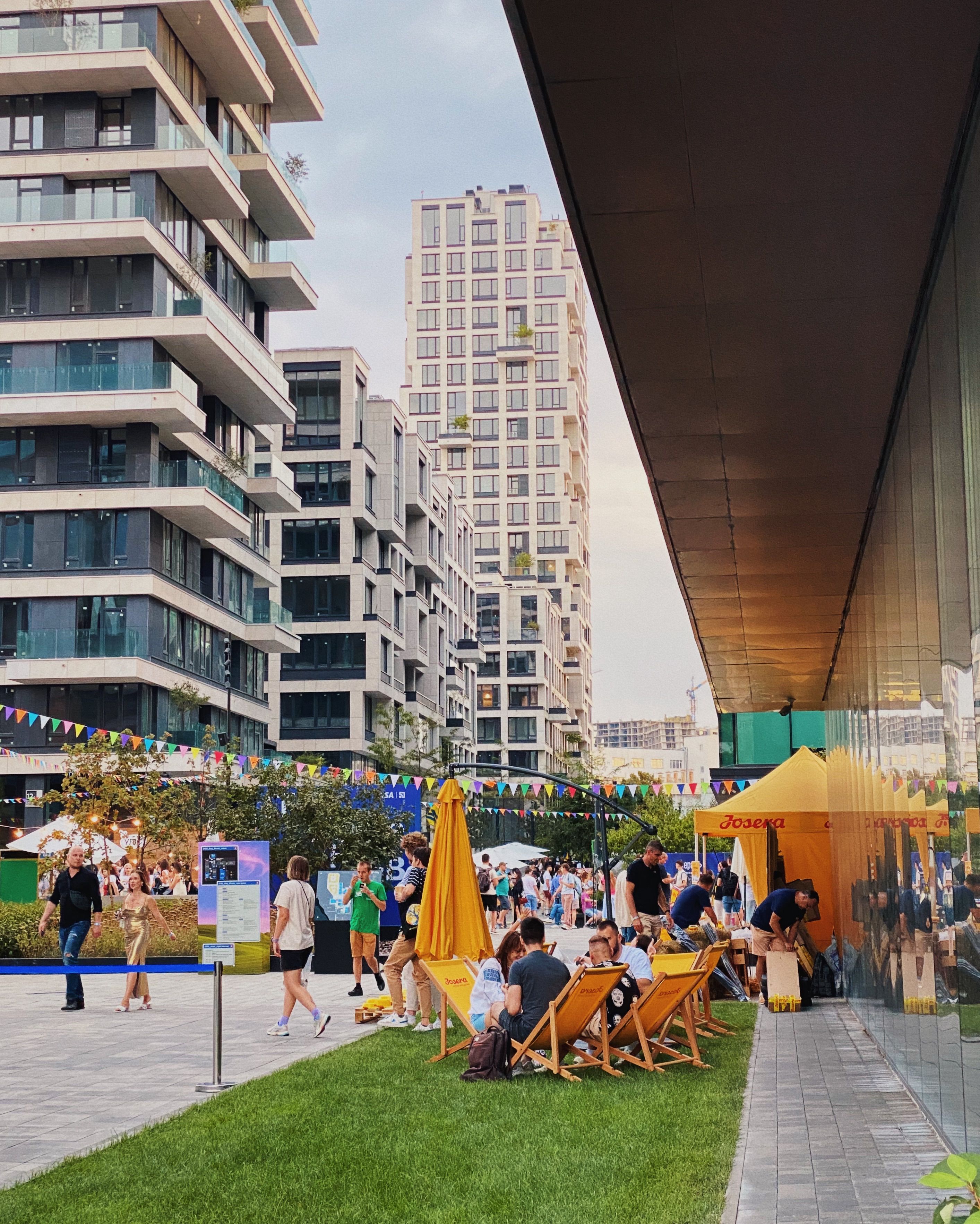 People sitting outside in a park with tall buildings · Free Stock Photo