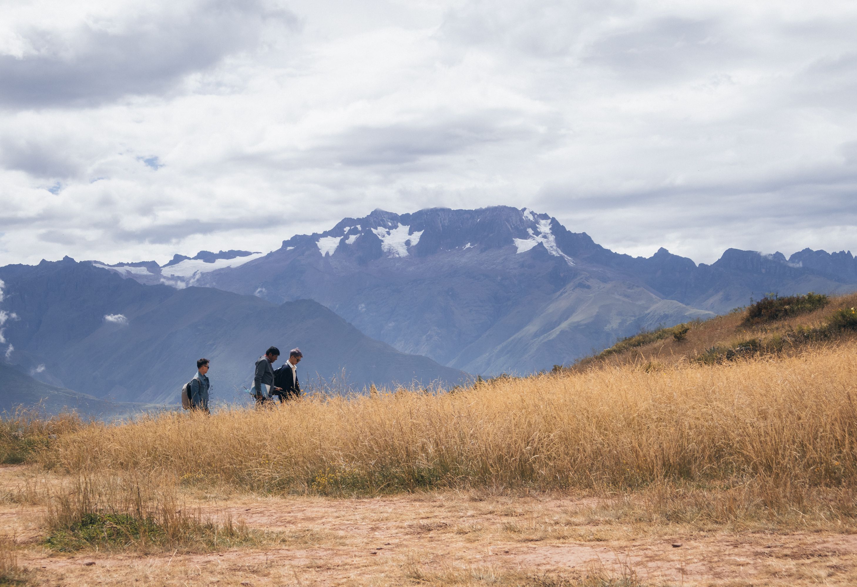 Two people walking in the mountains with mountains in the background ...