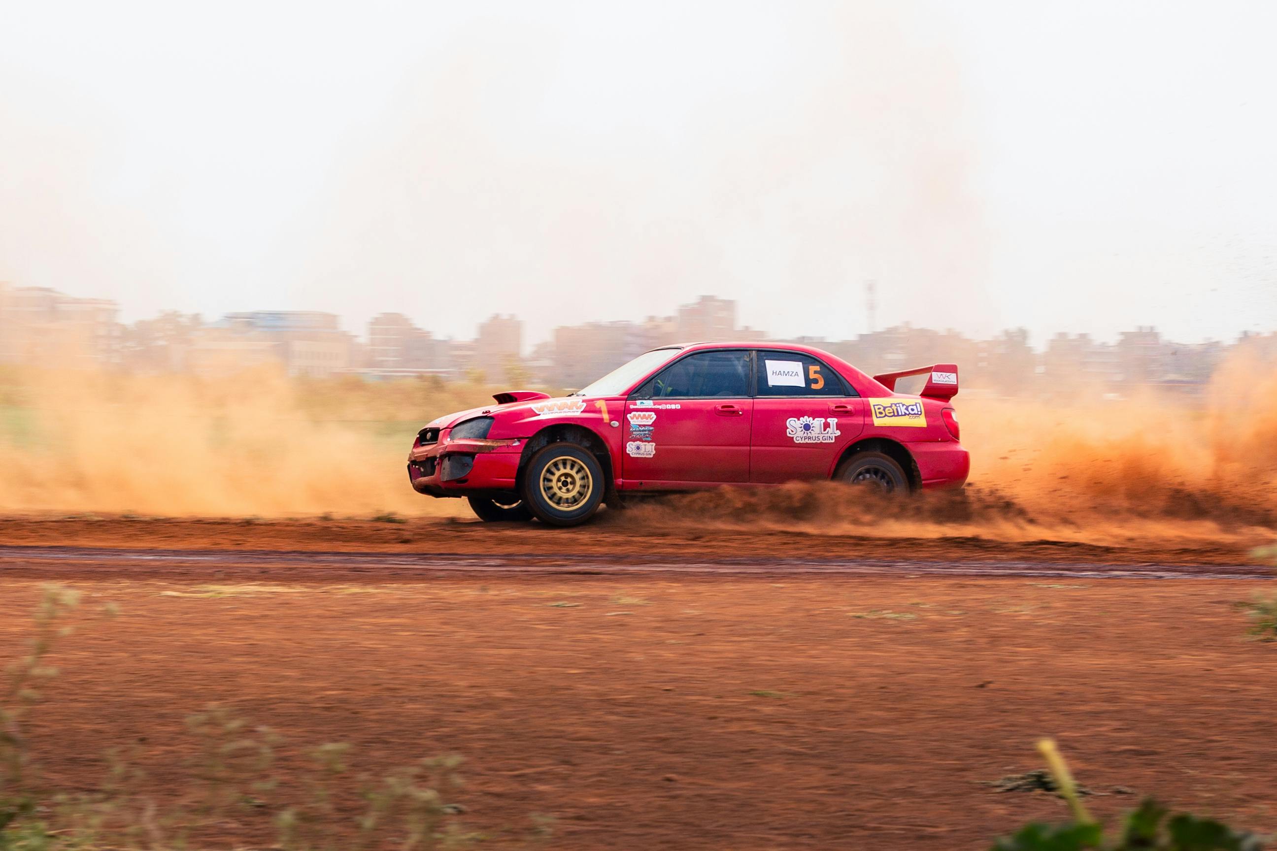 Dynamic Red Rally Car Racing on Dusty Track · Free Stock Photo