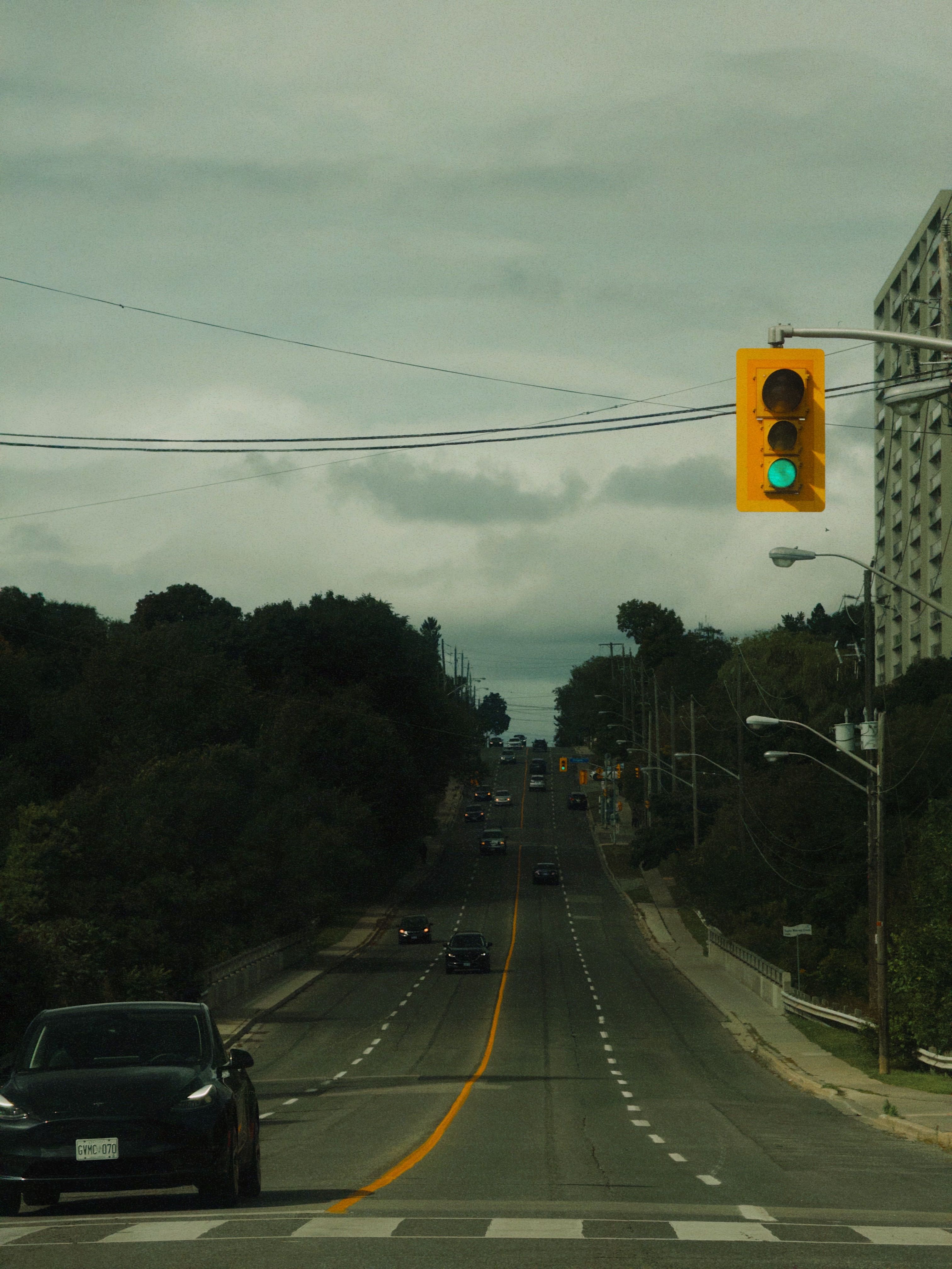 A traffic light on a street with cars driving by · Free Stock Photo