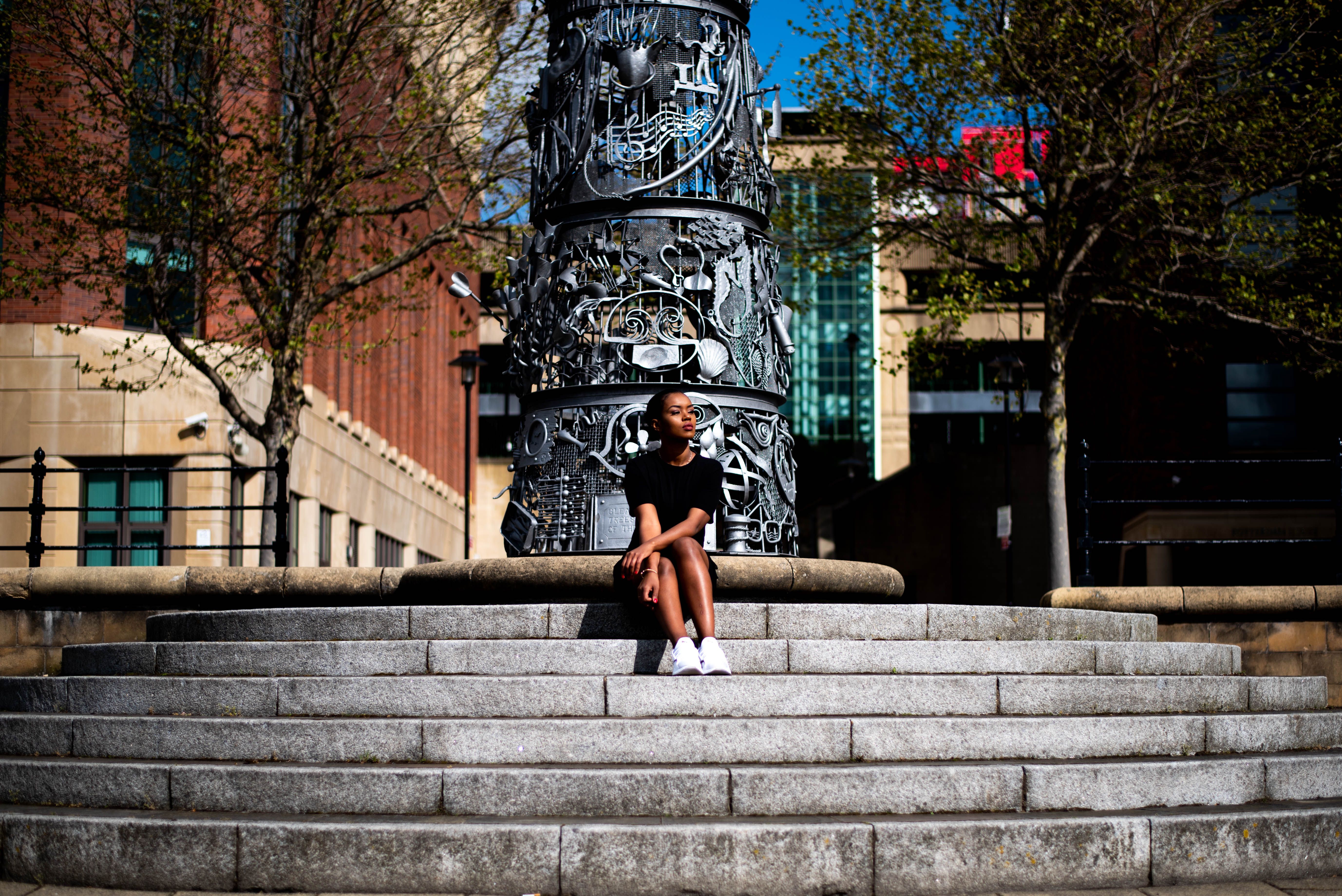A person sitting on a bench in front of a large statue · Free Stock Photo