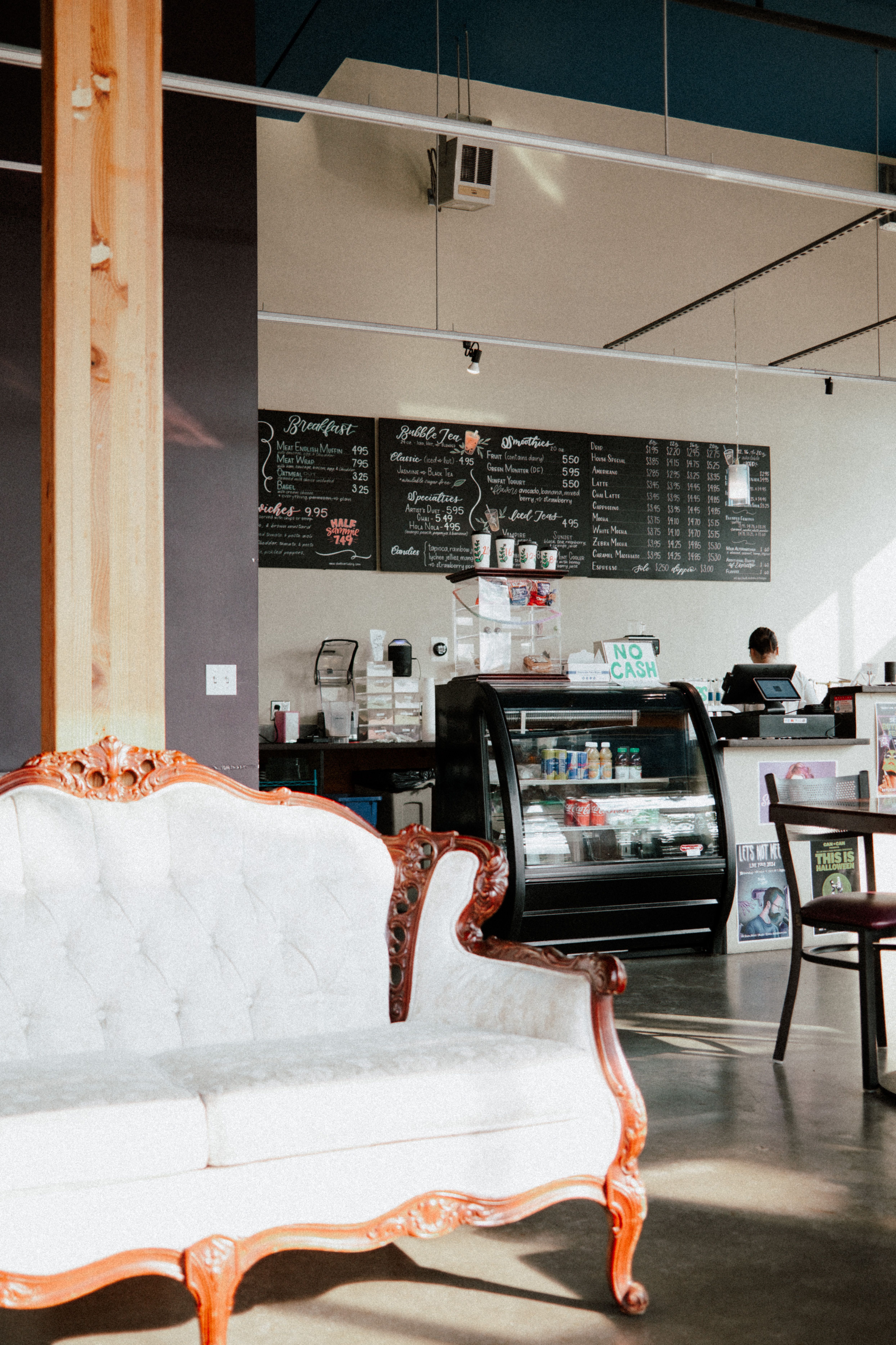 A white couch sits in front of a coffee shop · Free Stock Photo