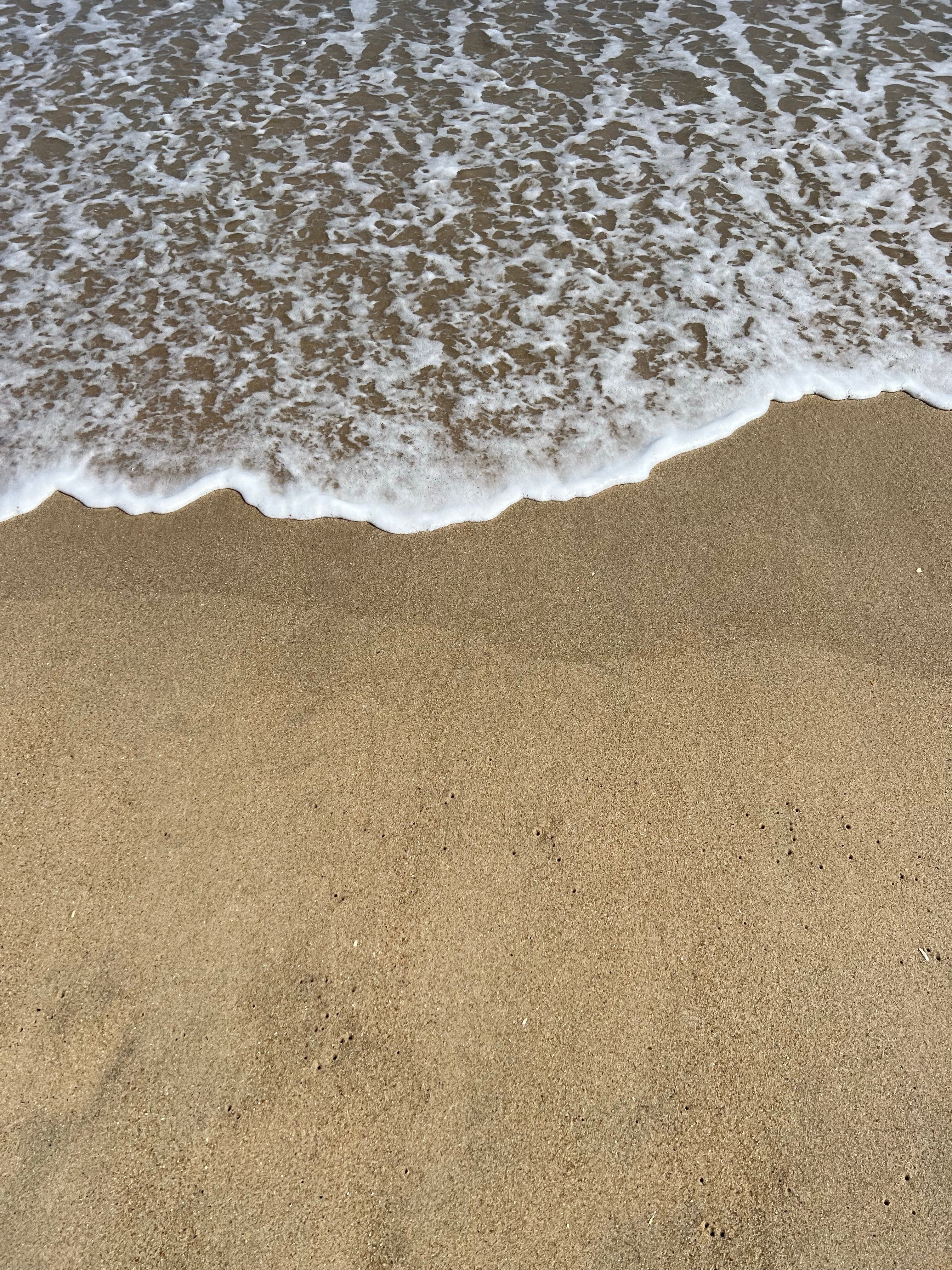 A Small Waves Crashing on Beach Sand with Footprints · Free Stock Photo