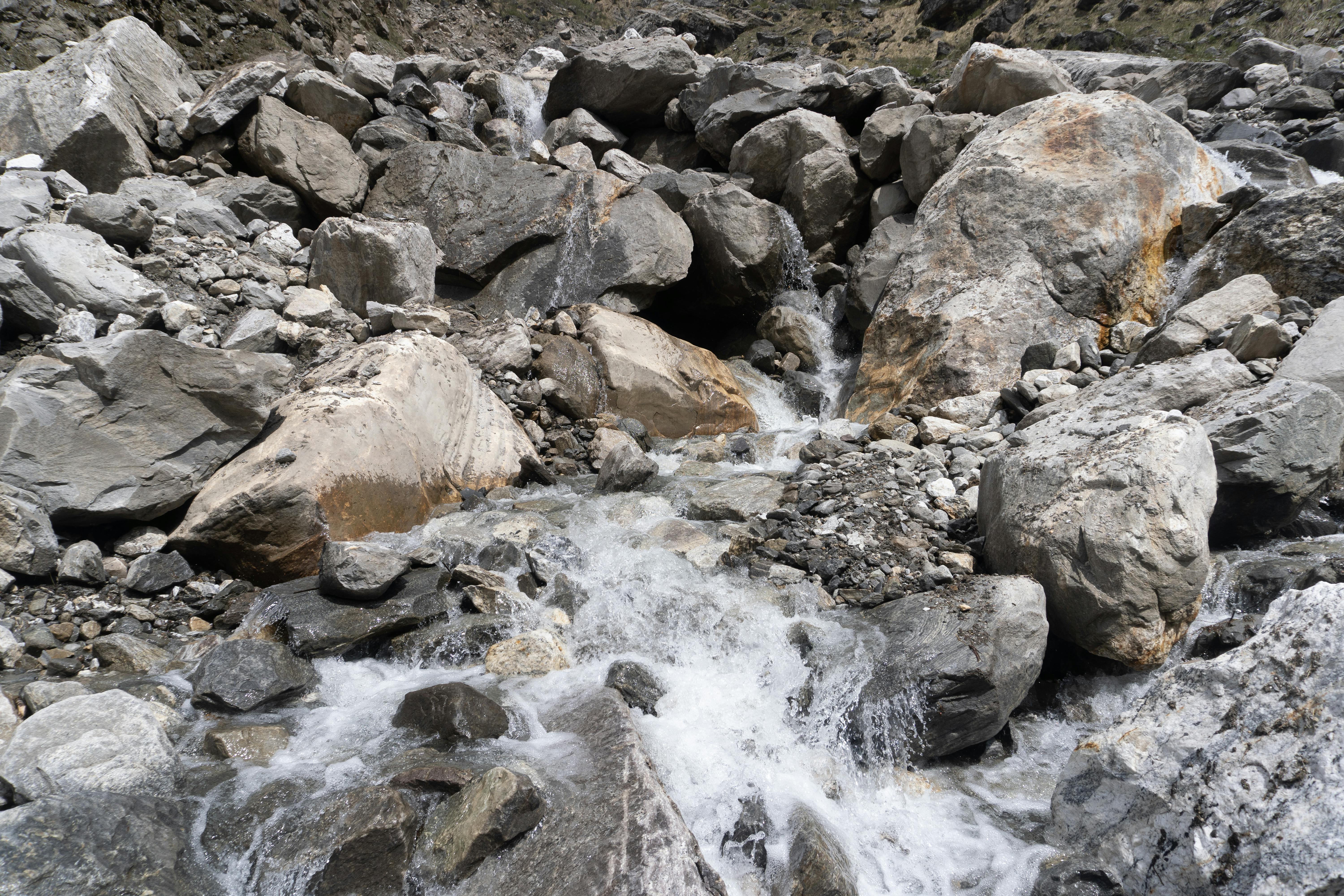 A stream of water flowing through rocks and boulders · Free Stock Photo