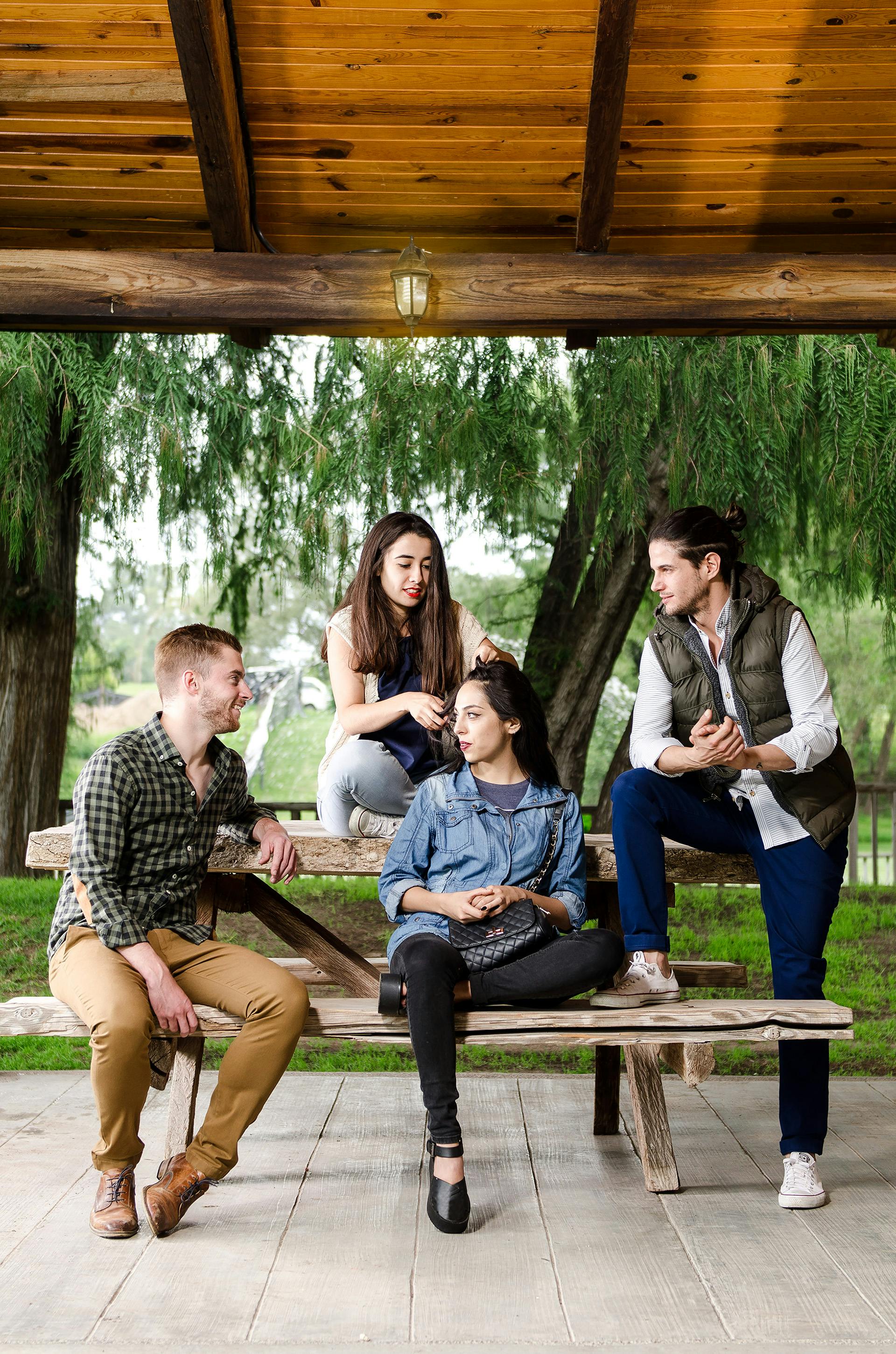 Friends Socializing Outdoors on Wooden Bench · Free Stock Photo