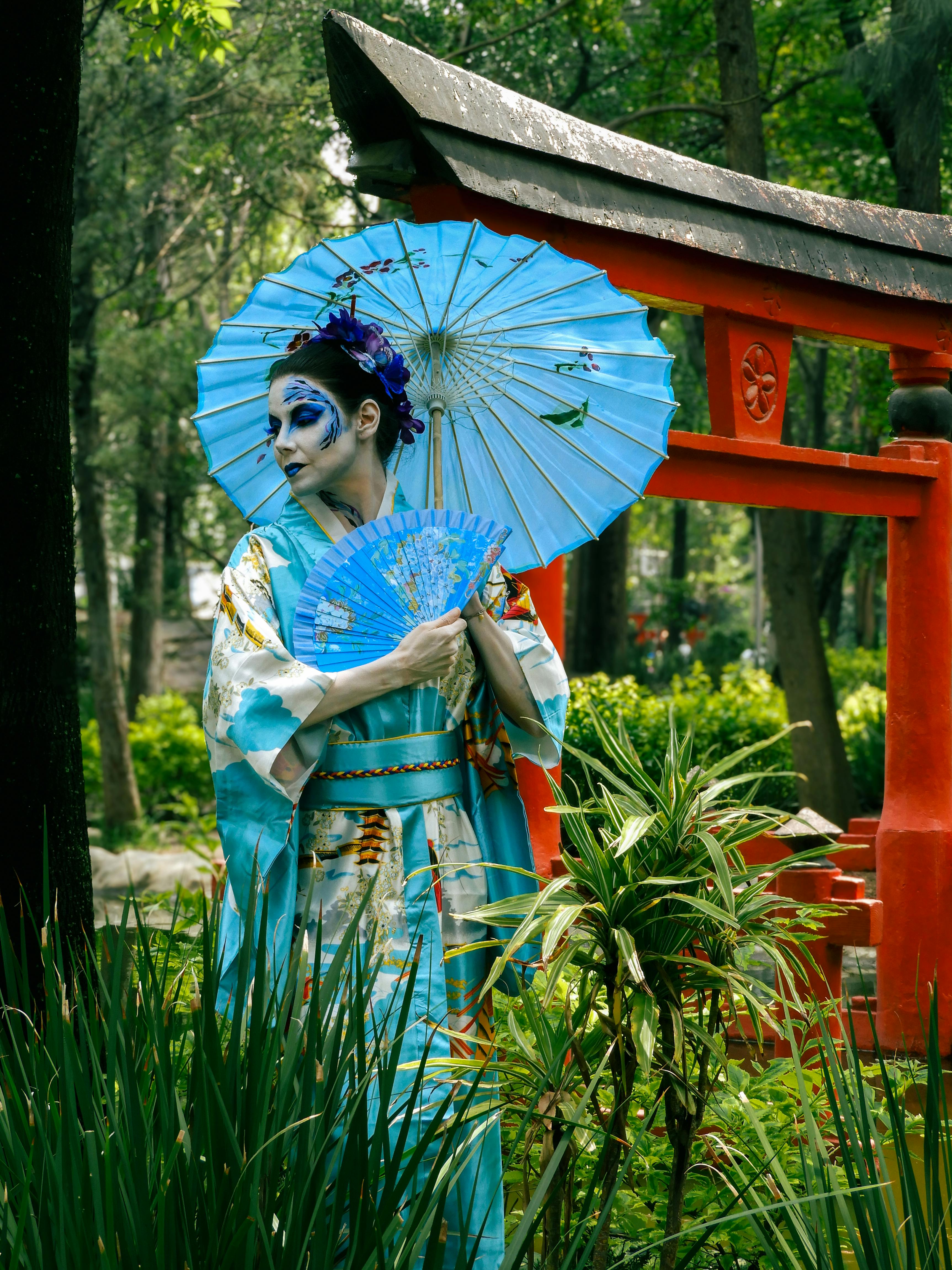 A woman dressed in a geisha costume holding a blue umbrella · Free ...