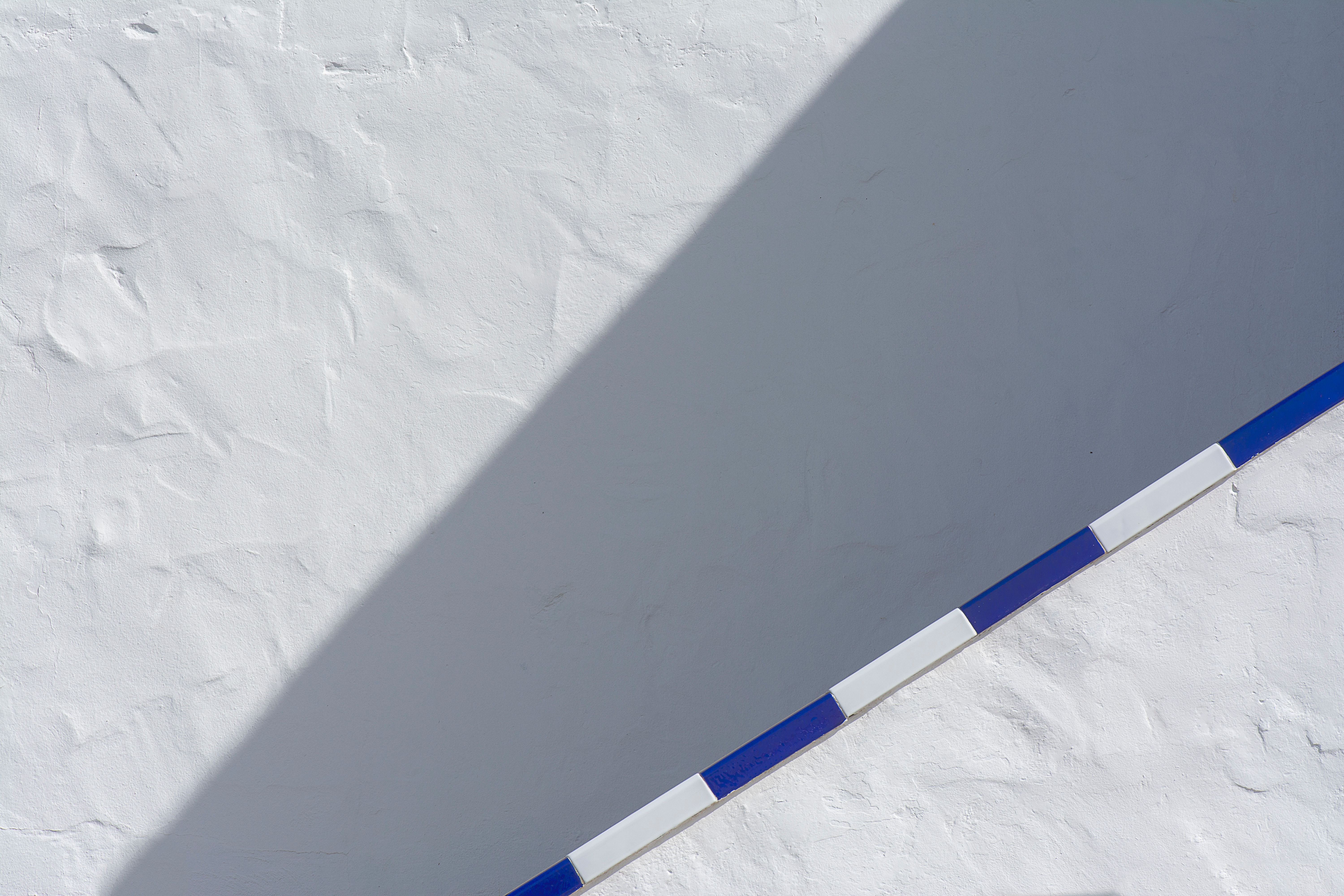 A blue and white striped wall with a shadow · Free Stock Photo