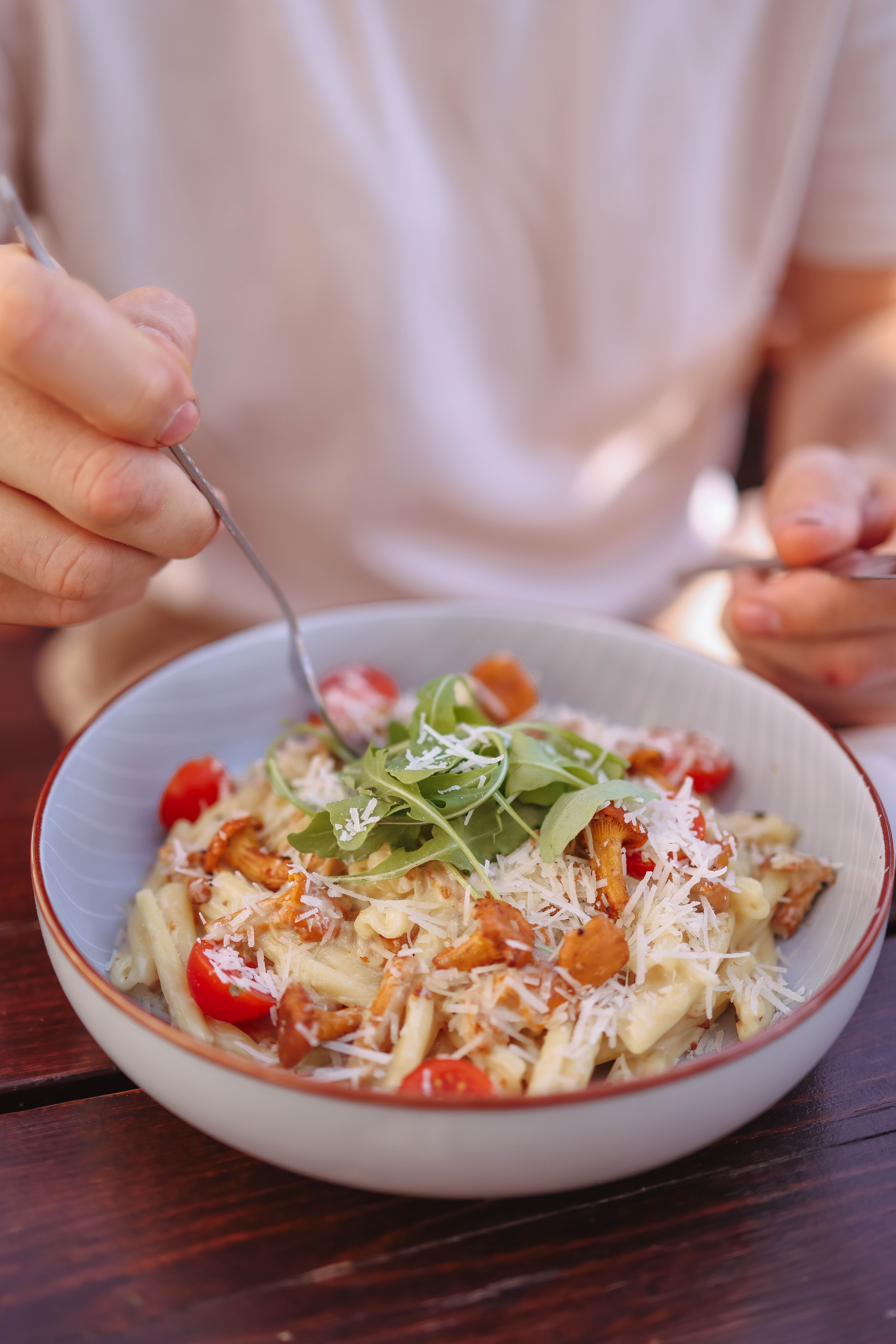 A person eating pasta with tomatoes and cheese · Free Stock Photo