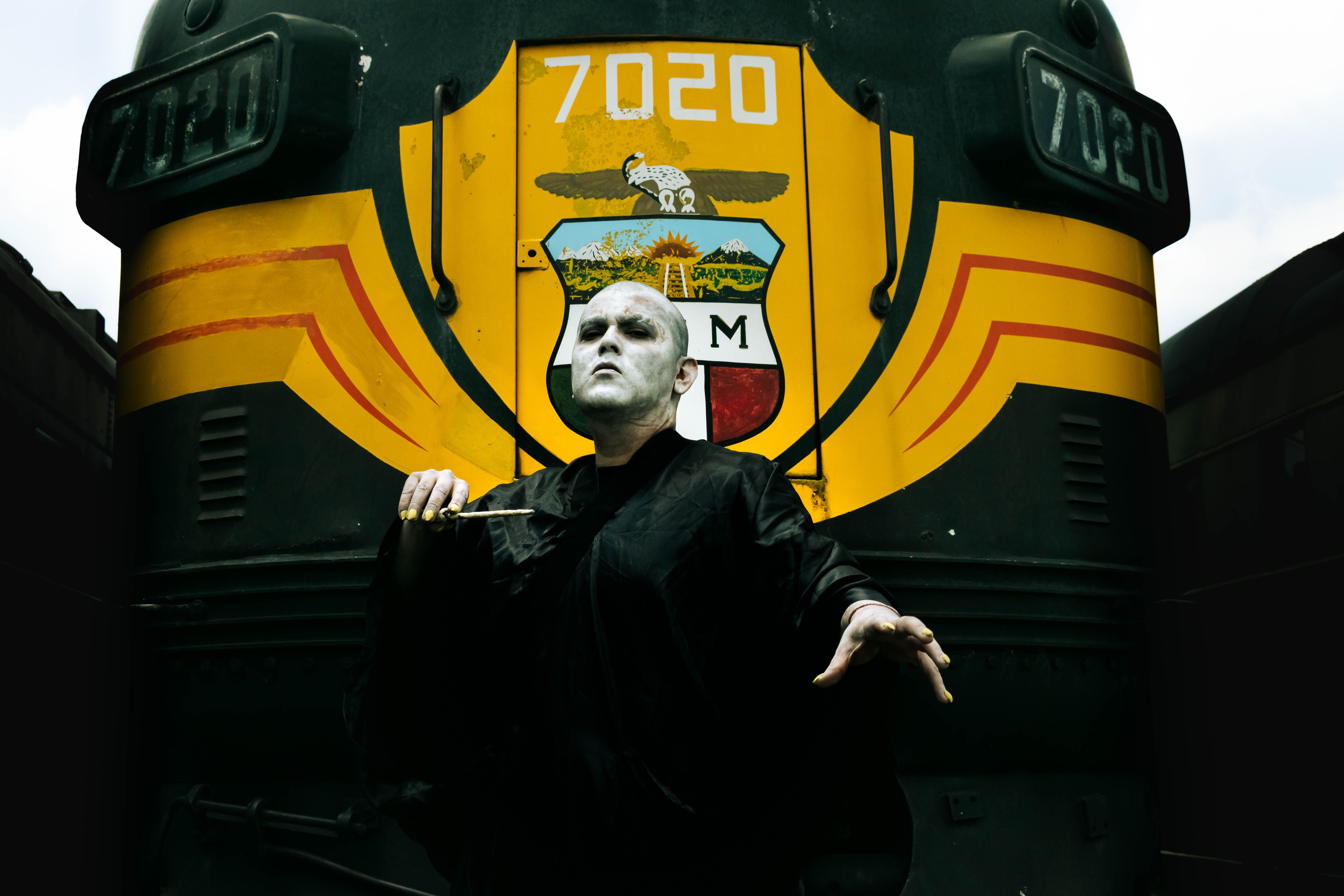A man in a mask standing next to a train · Free Stock Photo