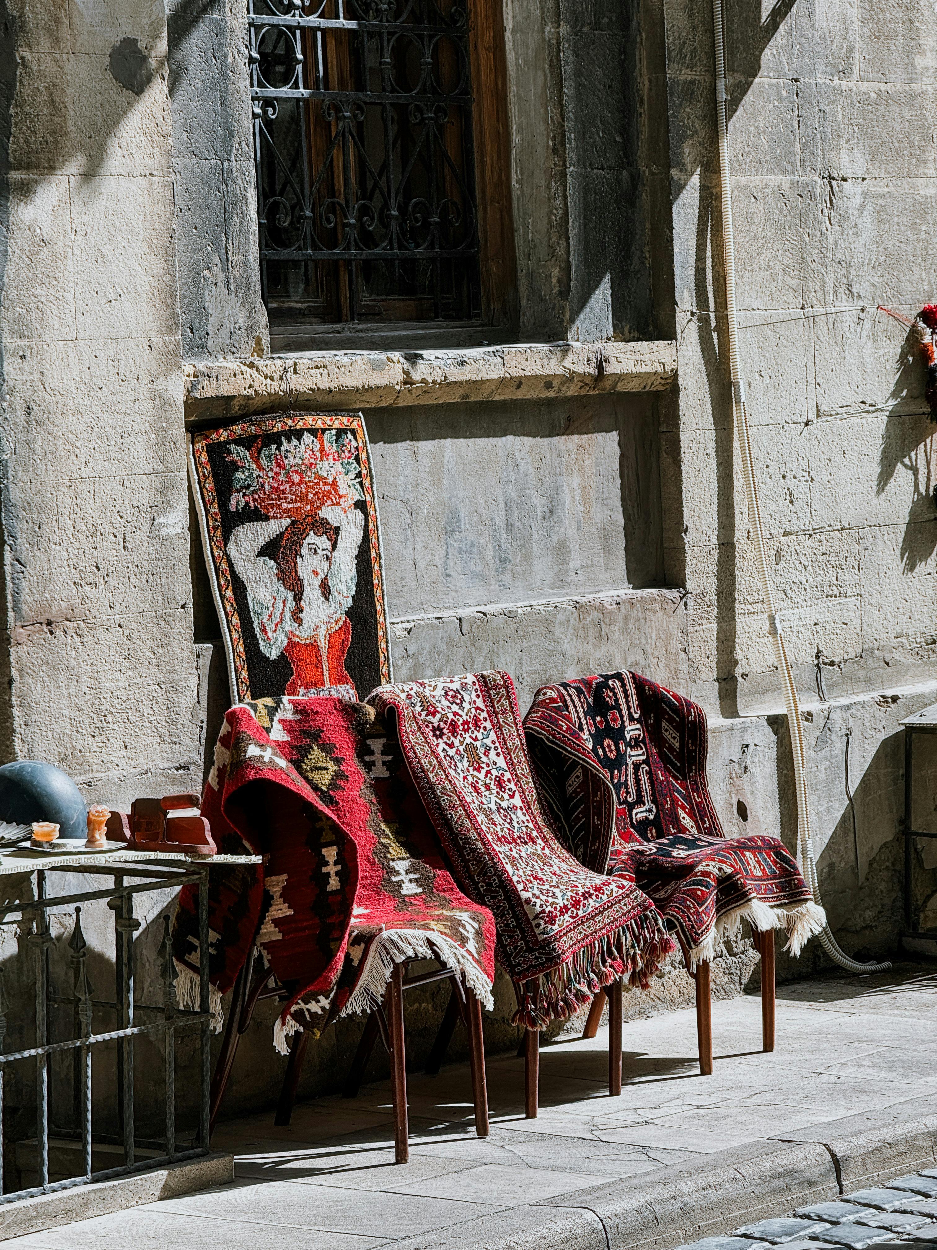 A group of rugs on the sidewalk in front of a building · Free Stock Photo
